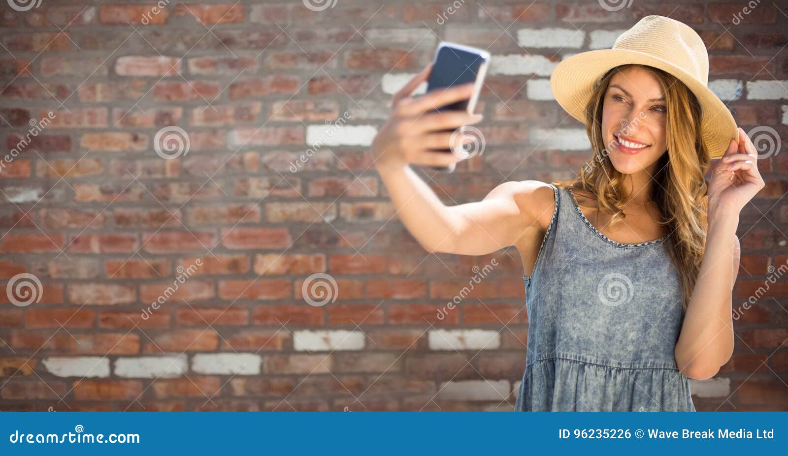 Millennial Woman In Summer Clothes Taking Selfie Against Red Brick Wall
