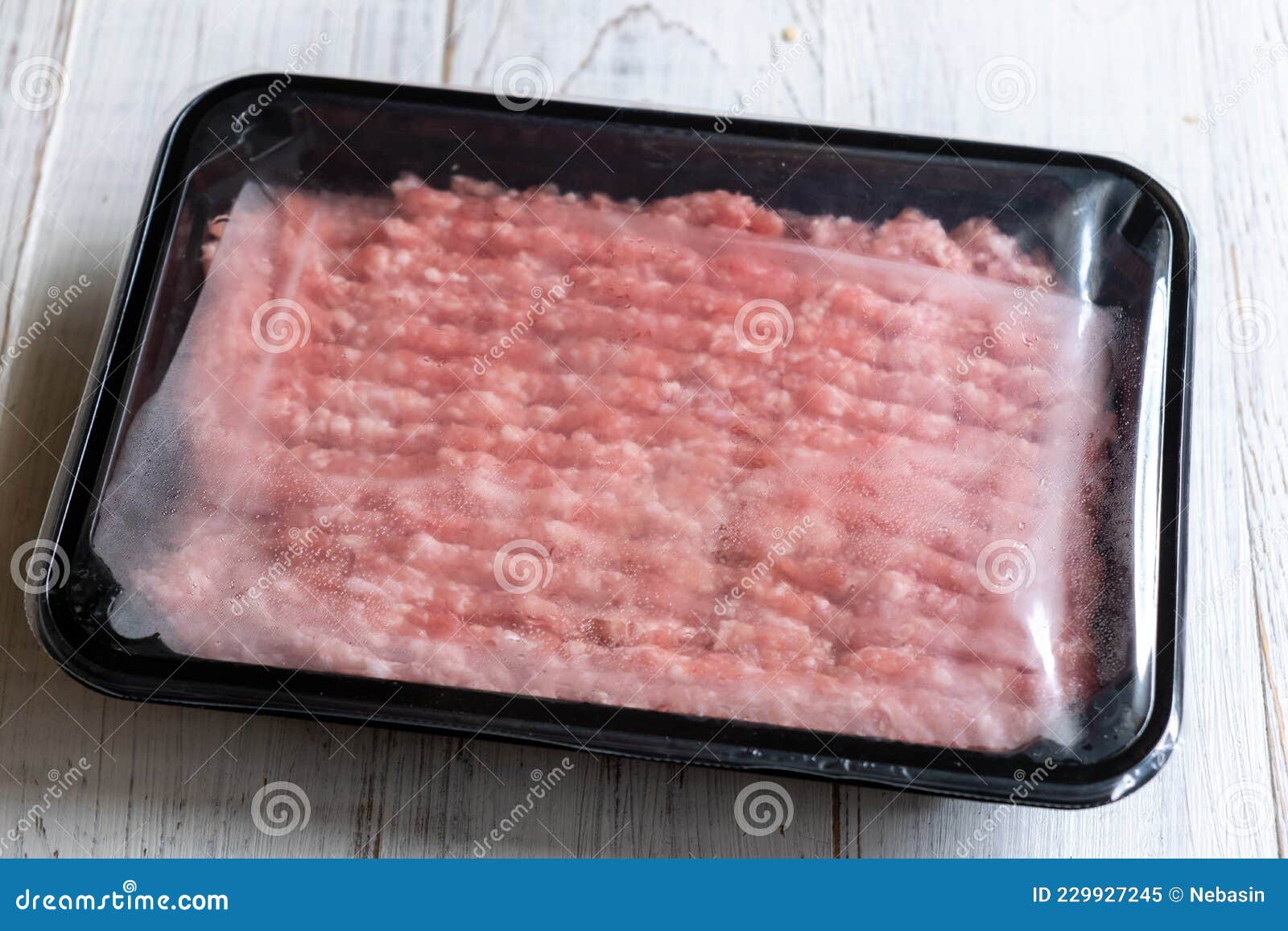 Minced Meat in Plastic Packaging on a Light Wooden Background Stock ...