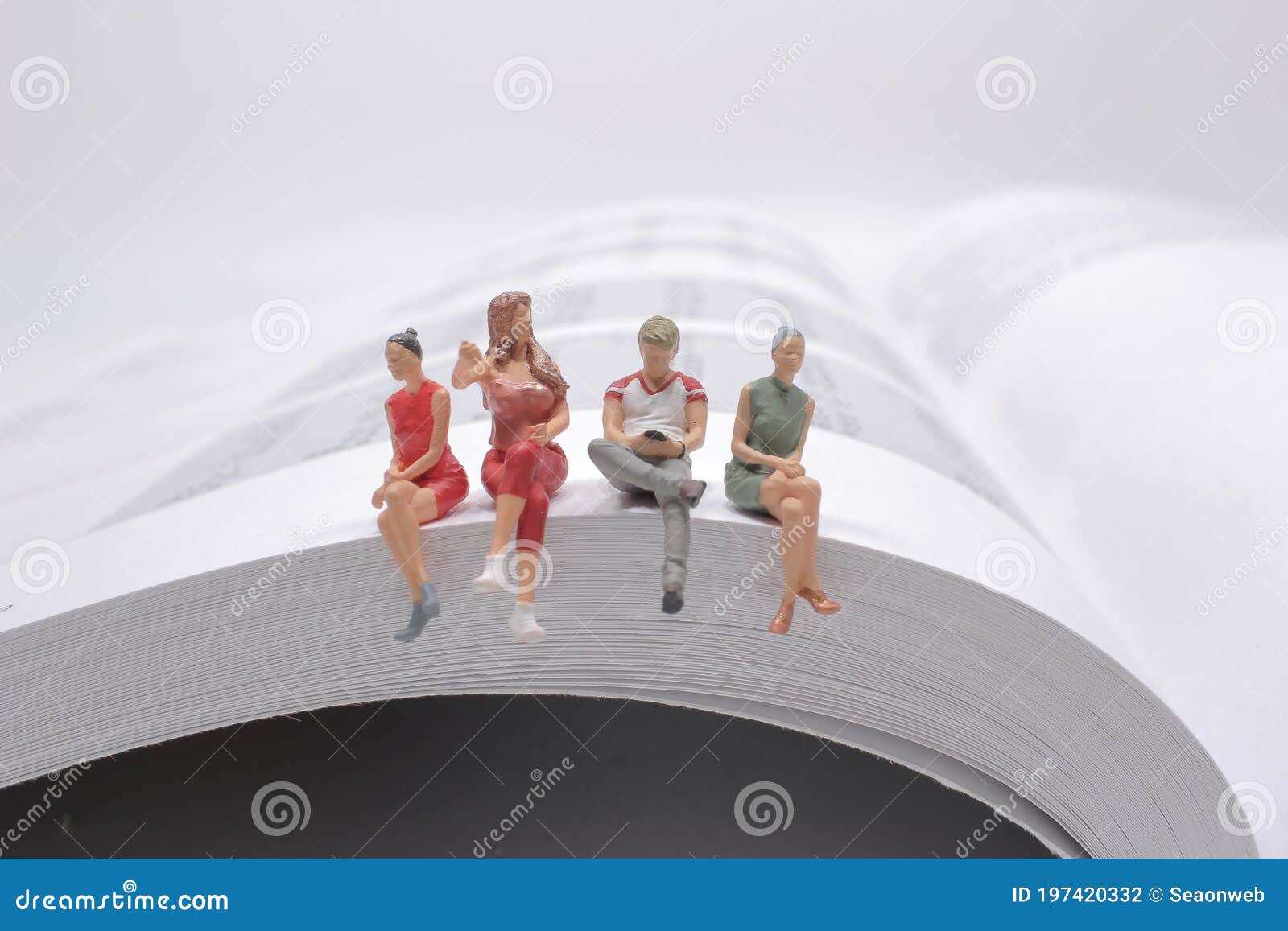 Mini Figure Reading Newspaper and Sitting on Book Stock Photo - Image ...