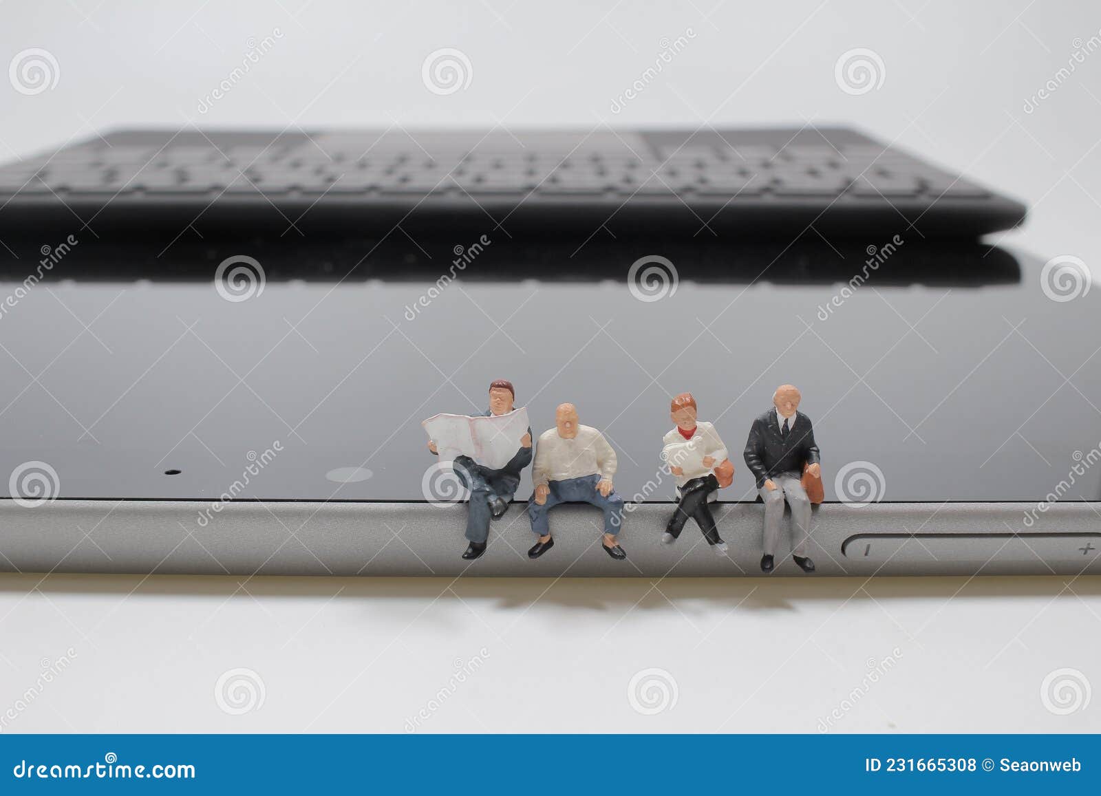 A Mini Figure Sitting on a Laptop while Working on a Laptop and Another ...