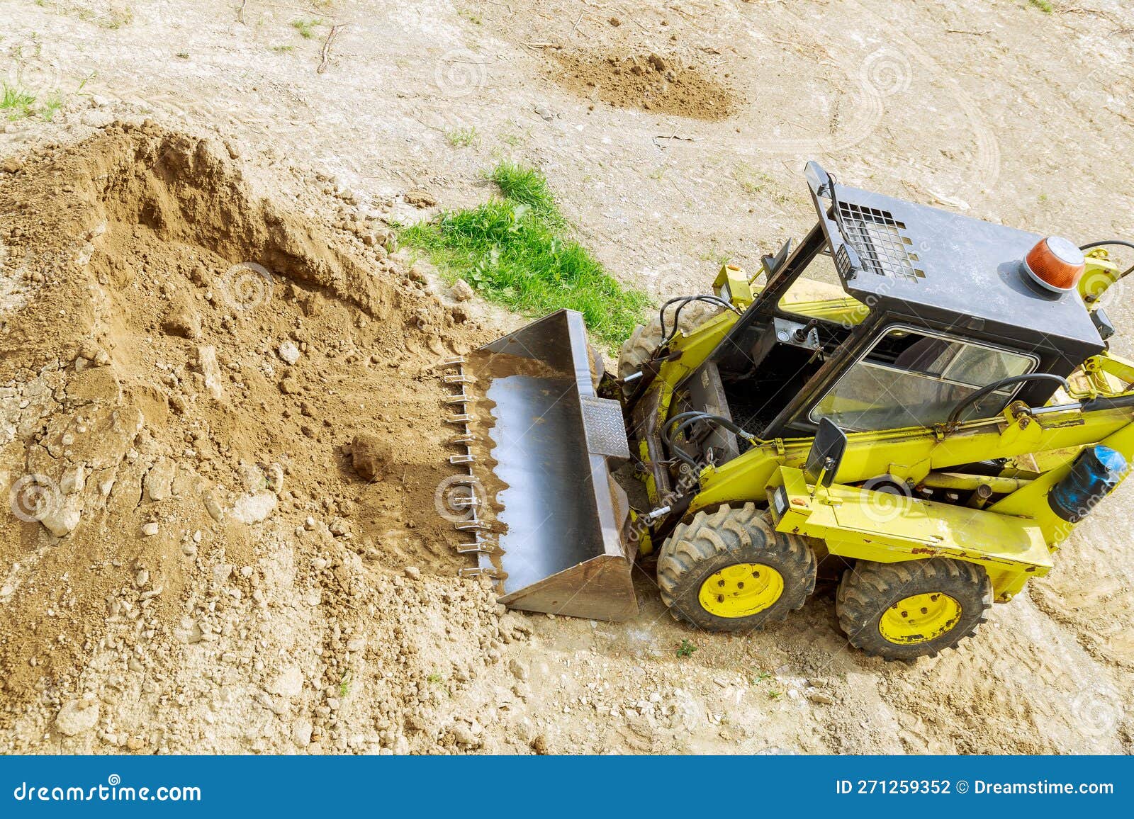 A Mini Tractor-loader Moves and Loads Earth on a Construction Site ...