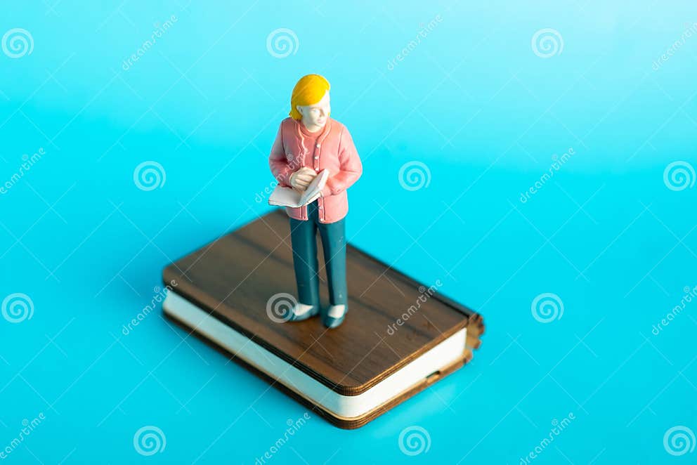 Miniature Figure Reading a Book Standing on a Notebook with Blue ...