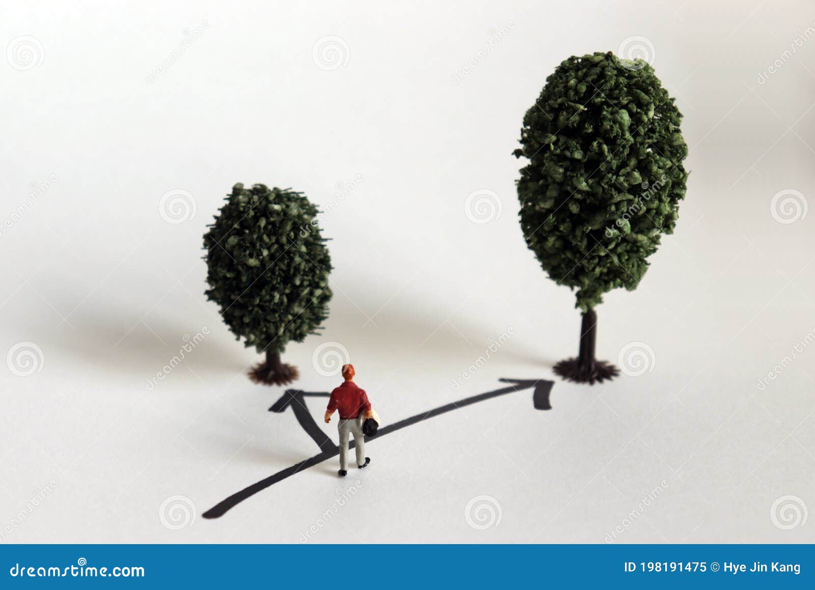 A Miniature Man Standing in Front of Two Trees of Different Sizes ...