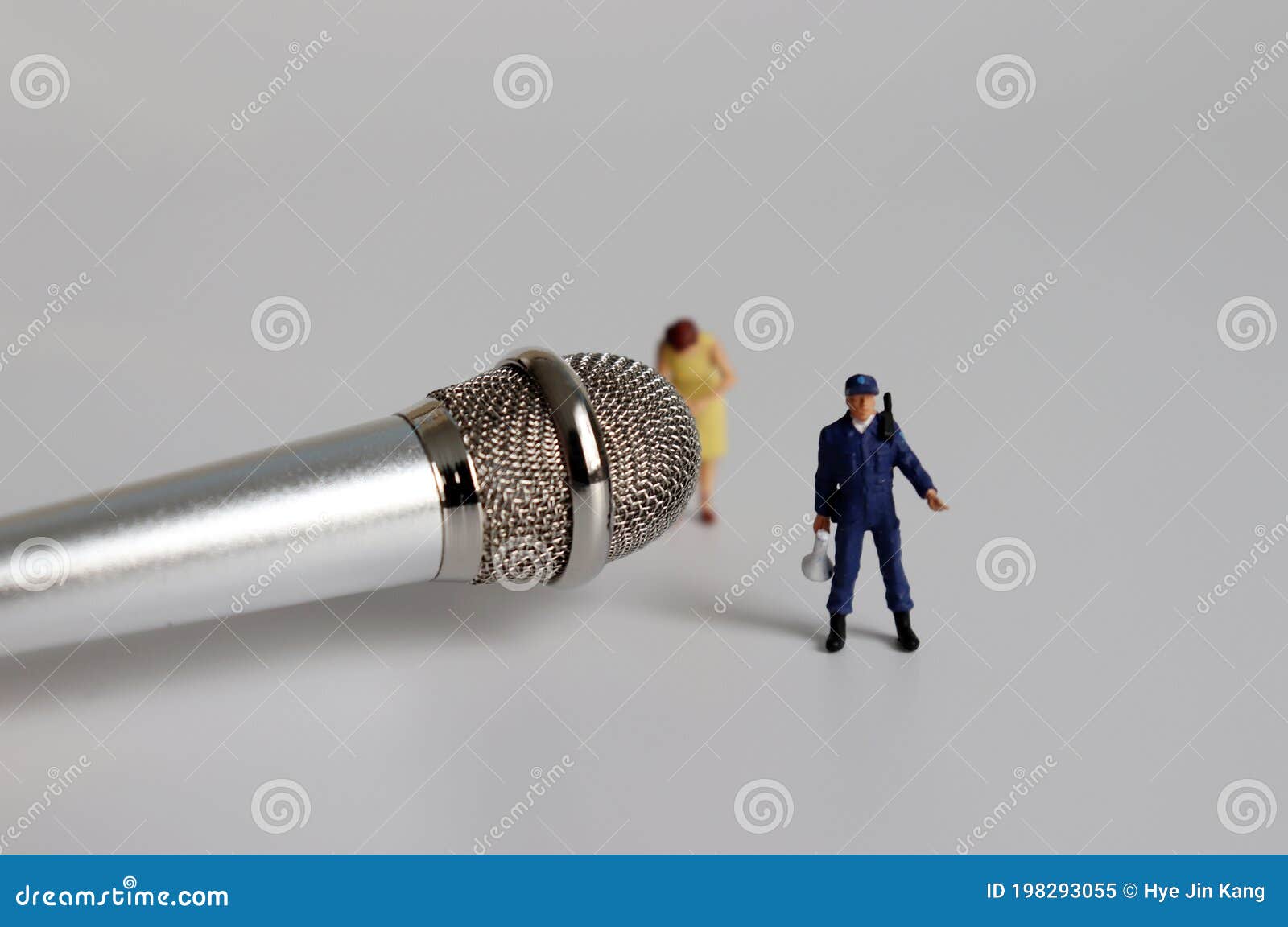A Miniature Woman Standing Behind a Microphone and a Miniature Police ...