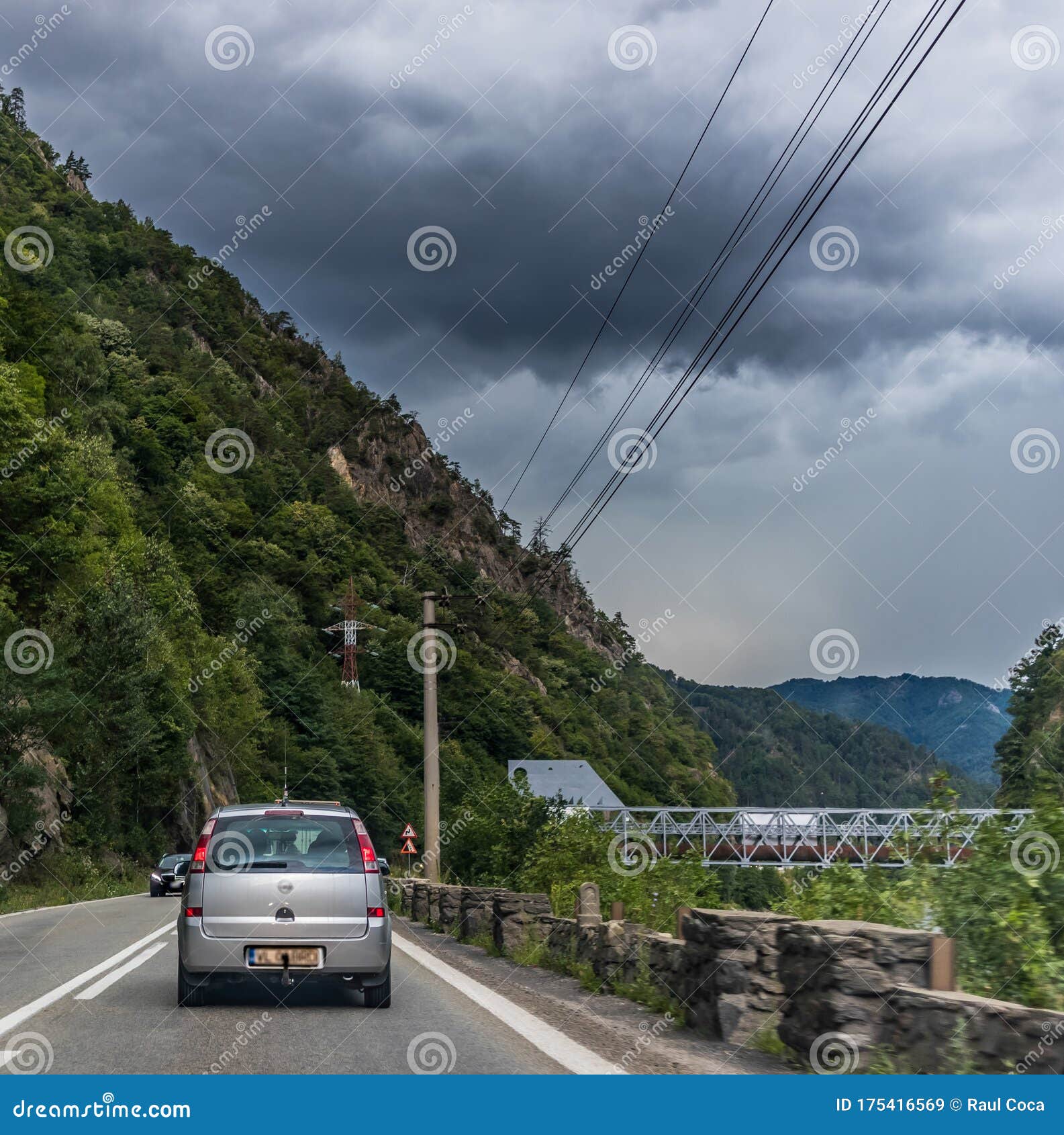 Minivan Passing on a Mountain Road with Stone Railing on the Right Side ...