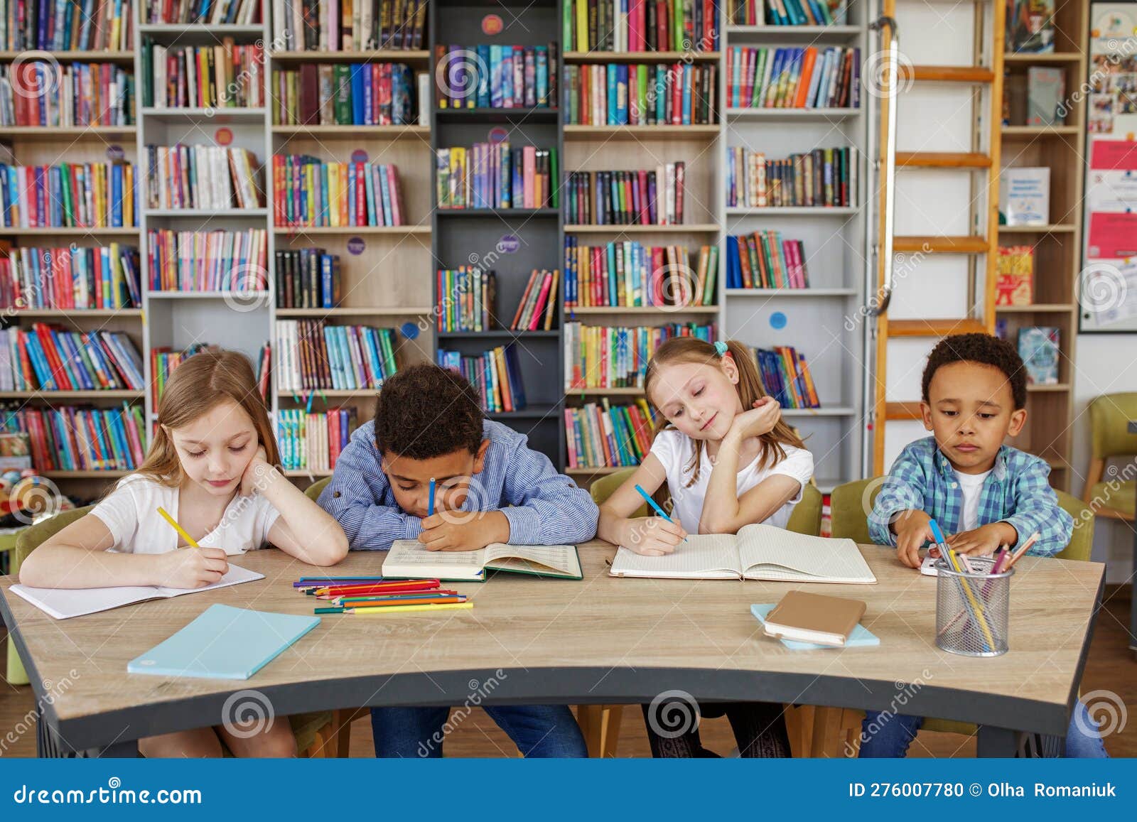 Mixed-race Pupils Study and Write at Table in Library or Classroom ...