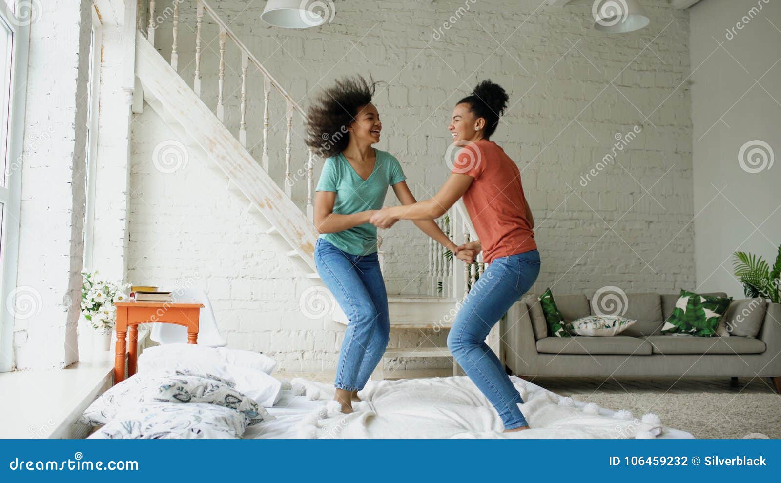 Mixed Race Young Beautiful Girls Dancing On A Bed Together Having Fun