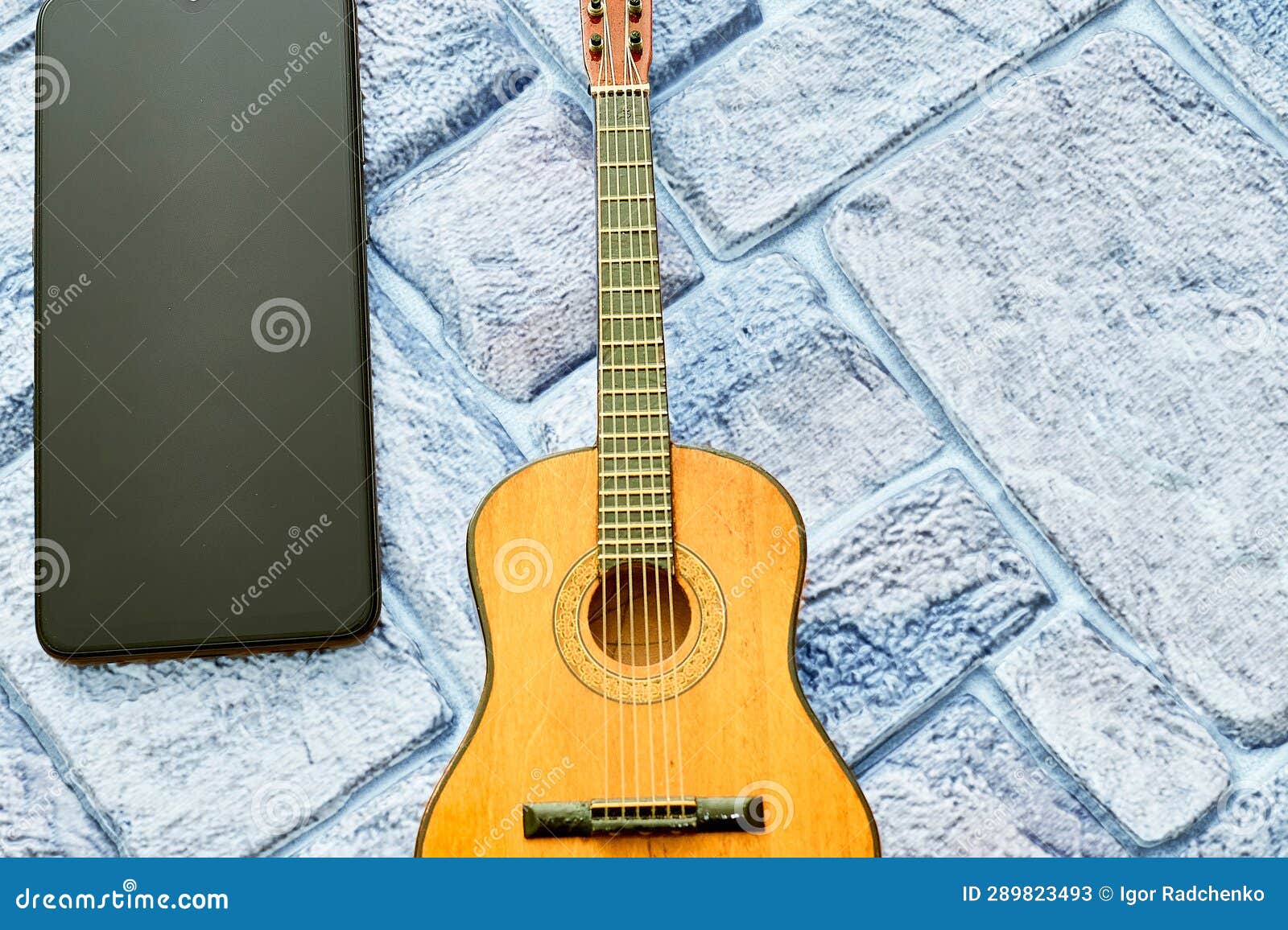 Mobile Phone and Acoustic Guitar on a Blue Silver Brick Surface Stock ...