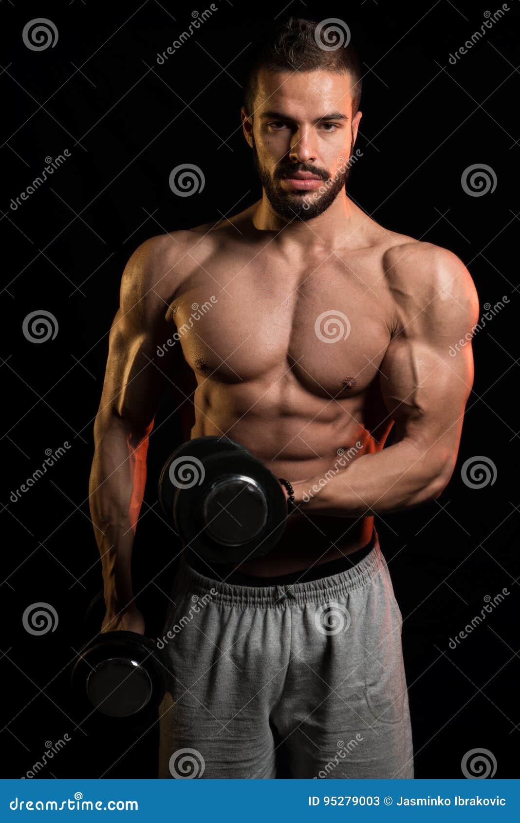 Model Exercising Biceps with Dumbbells on Black Background Stock Image ...