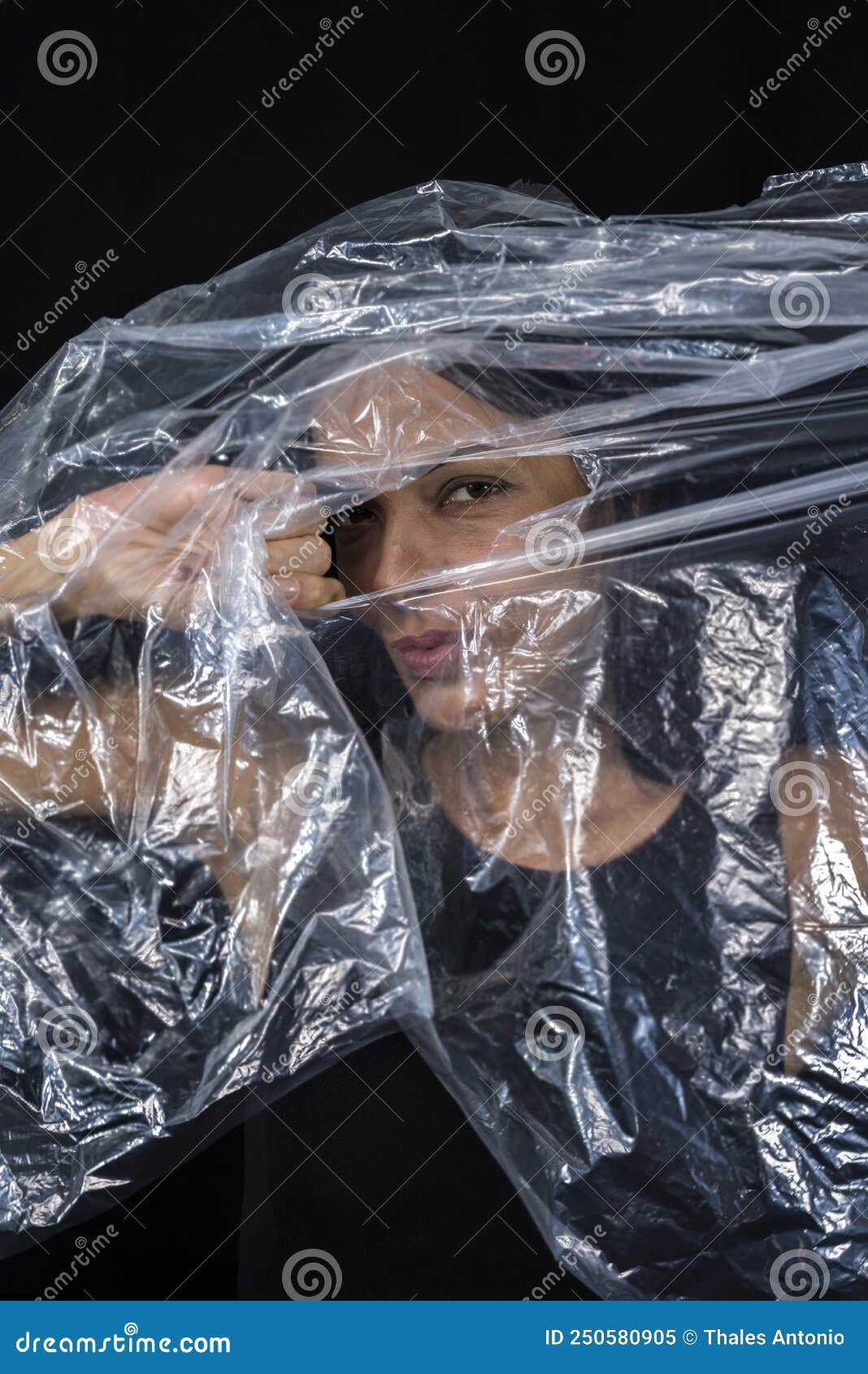 Model Portrait with Clear Plastic in Front of Her Face Against Black ...