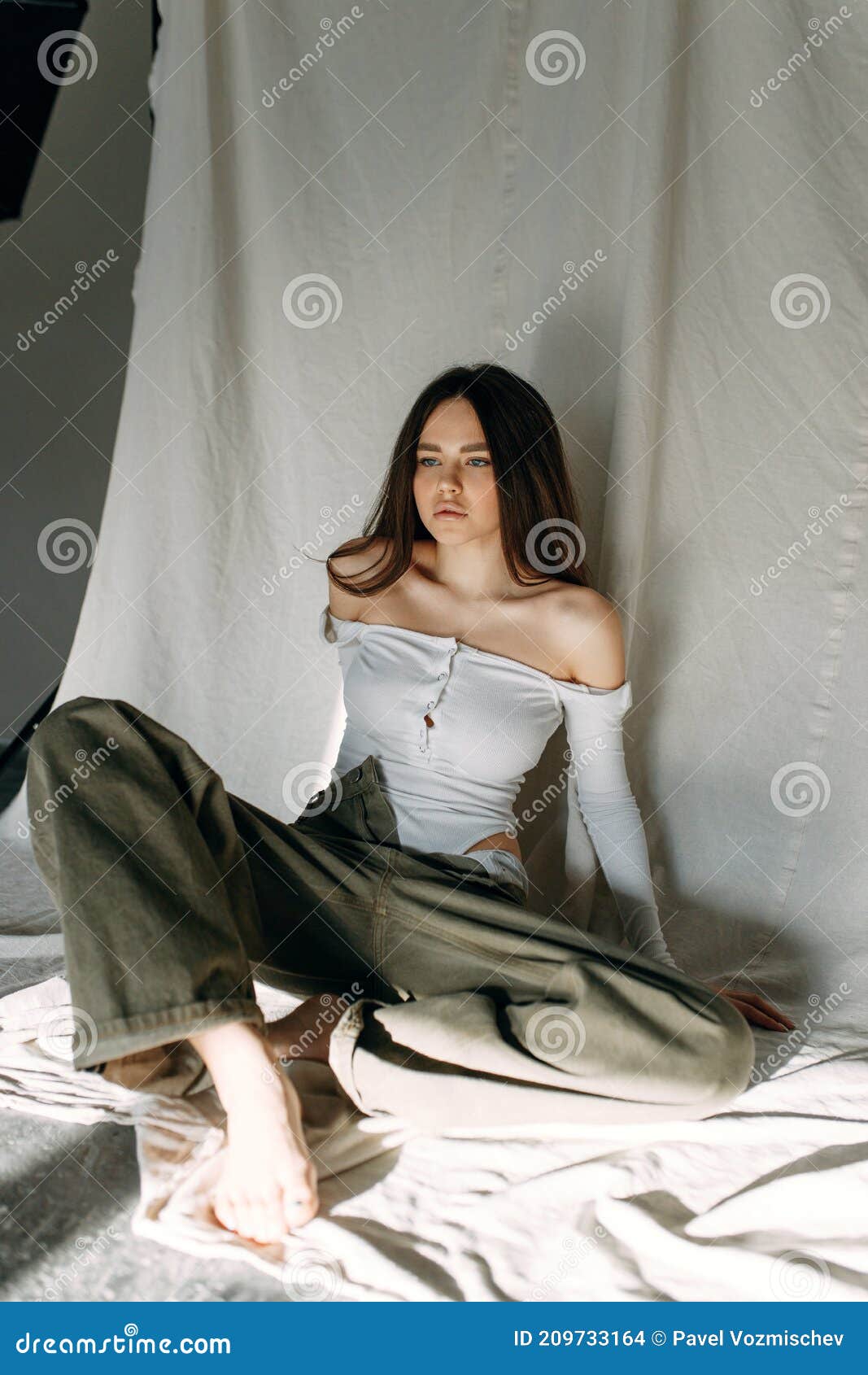 Portrait Of A Young Skinny Brunette Posing In A White Bodysuit Sitting