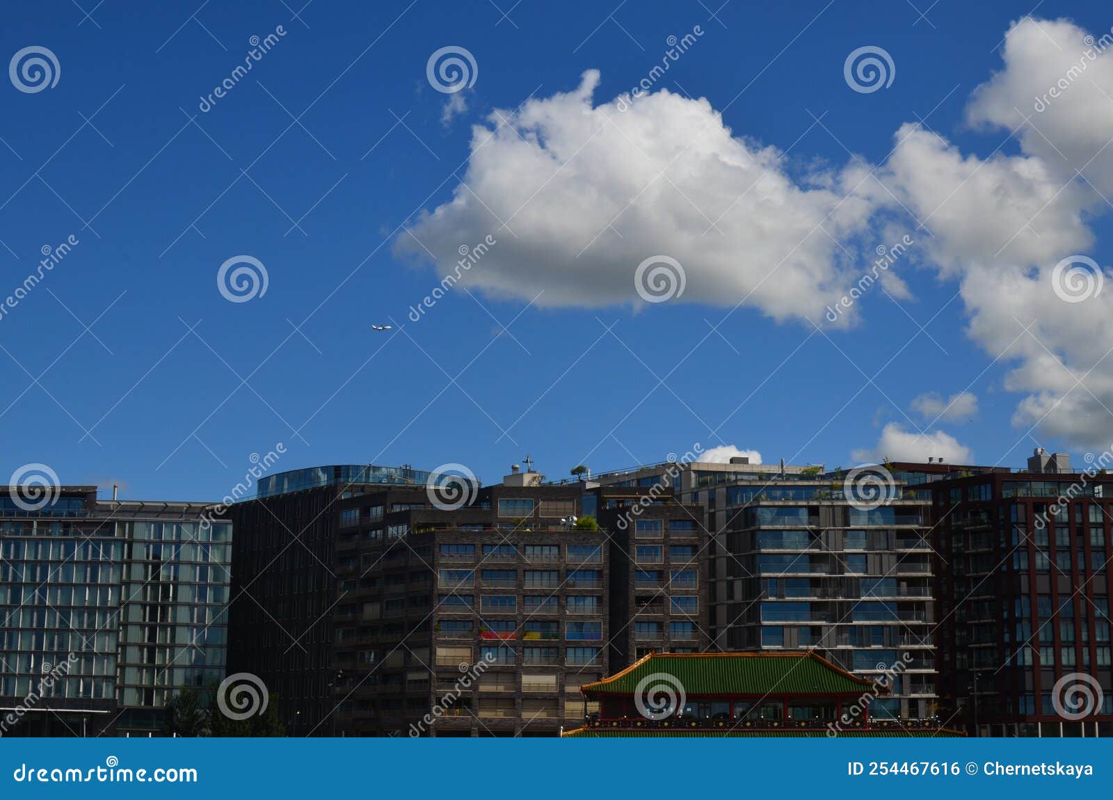 Modern Airplane in Sky Over Buildings on Sunny Day Stock Photo - Image ...