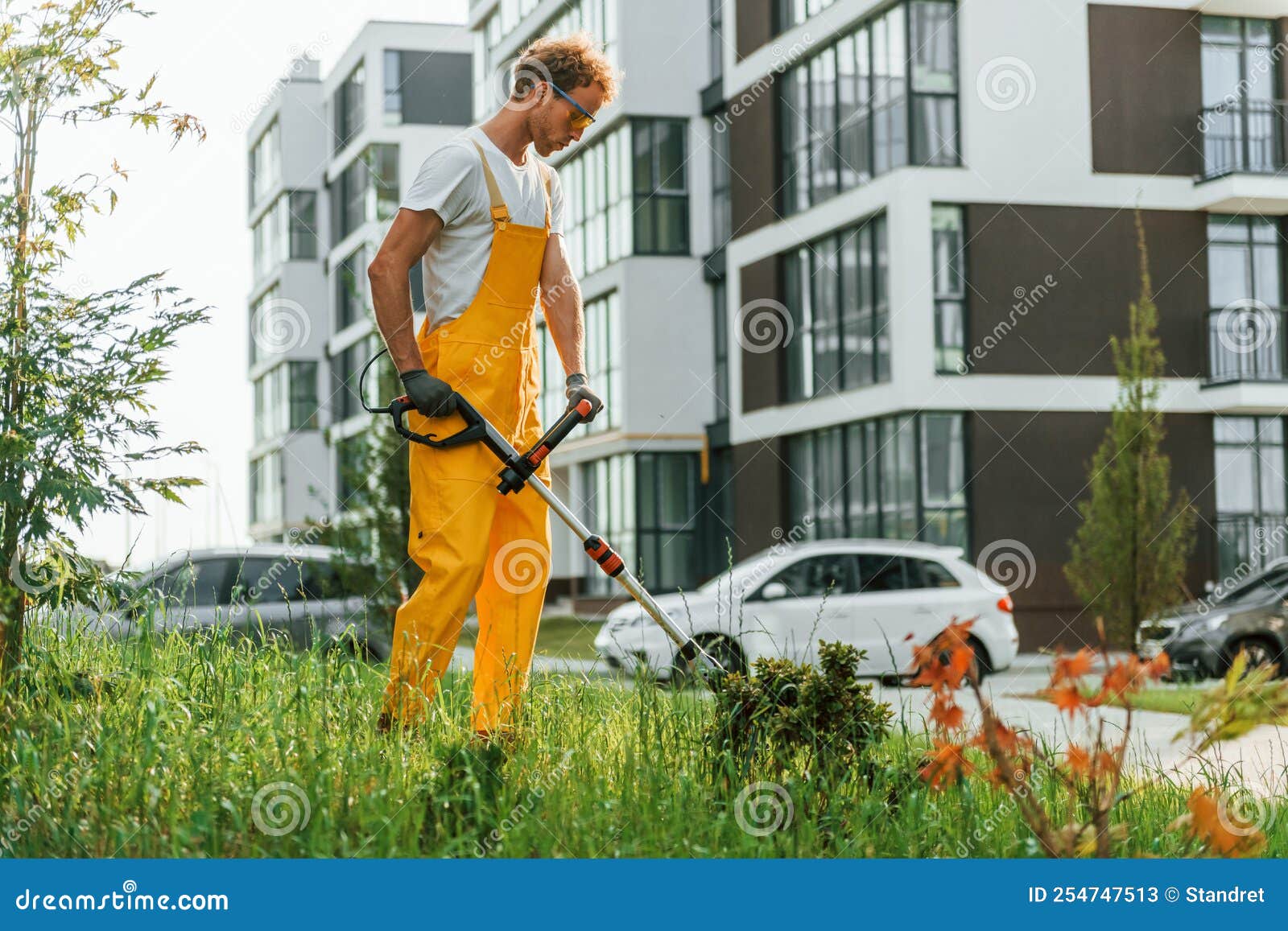 Modern Buildings. Man Cut the Grass with Lawn Mover Outdoors in the ...