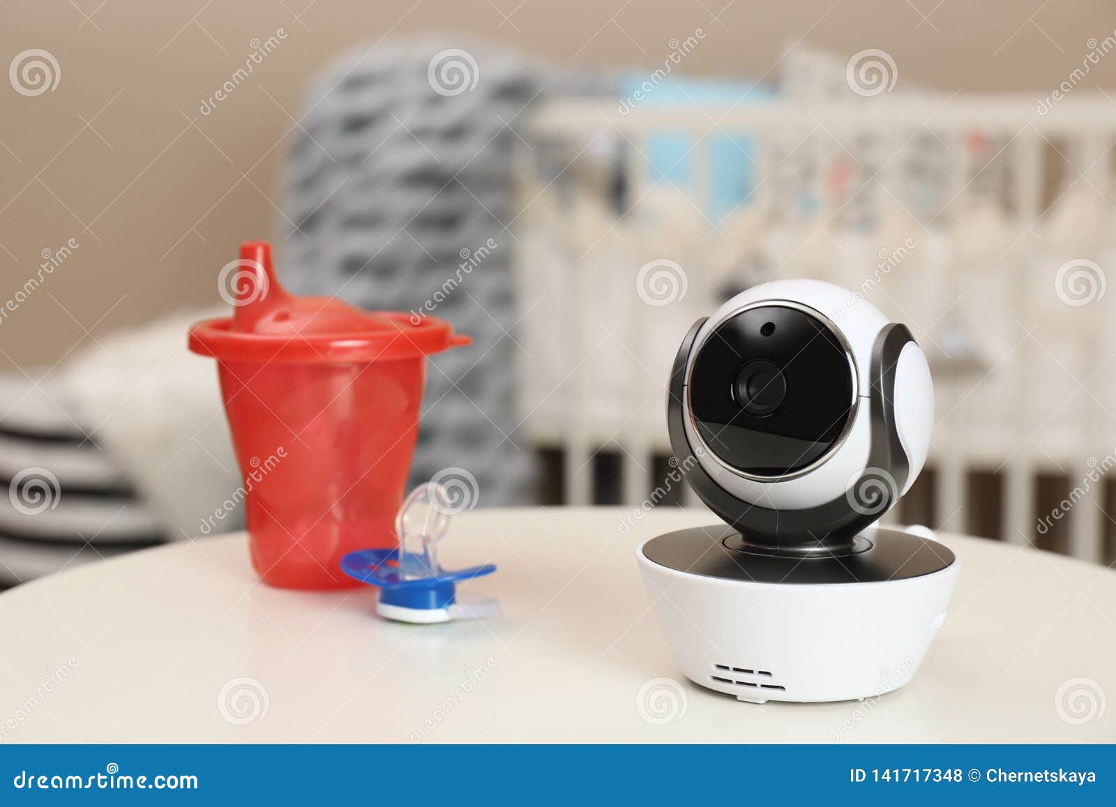 Modern CCTV Security Camera, Baby Cup and Pacifier on Table Stock Photo ...