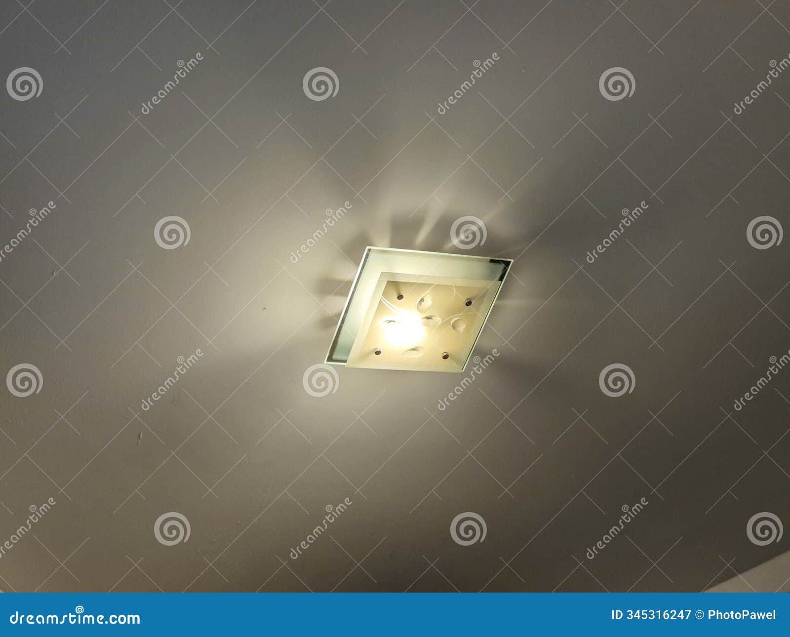 A Modern Ceiling Light Fixture Casting Soft Shadows on a Gray Surface ...