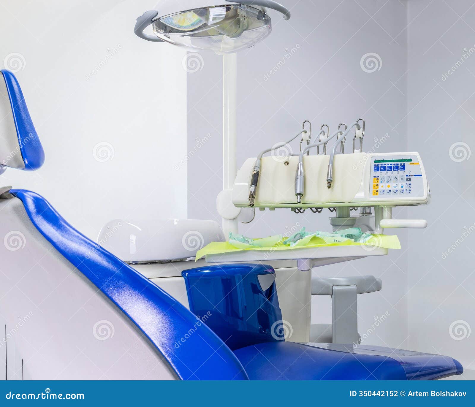 Modern Dental Equipment Setup with Blue Chair, Overhead Lamp, Control ...