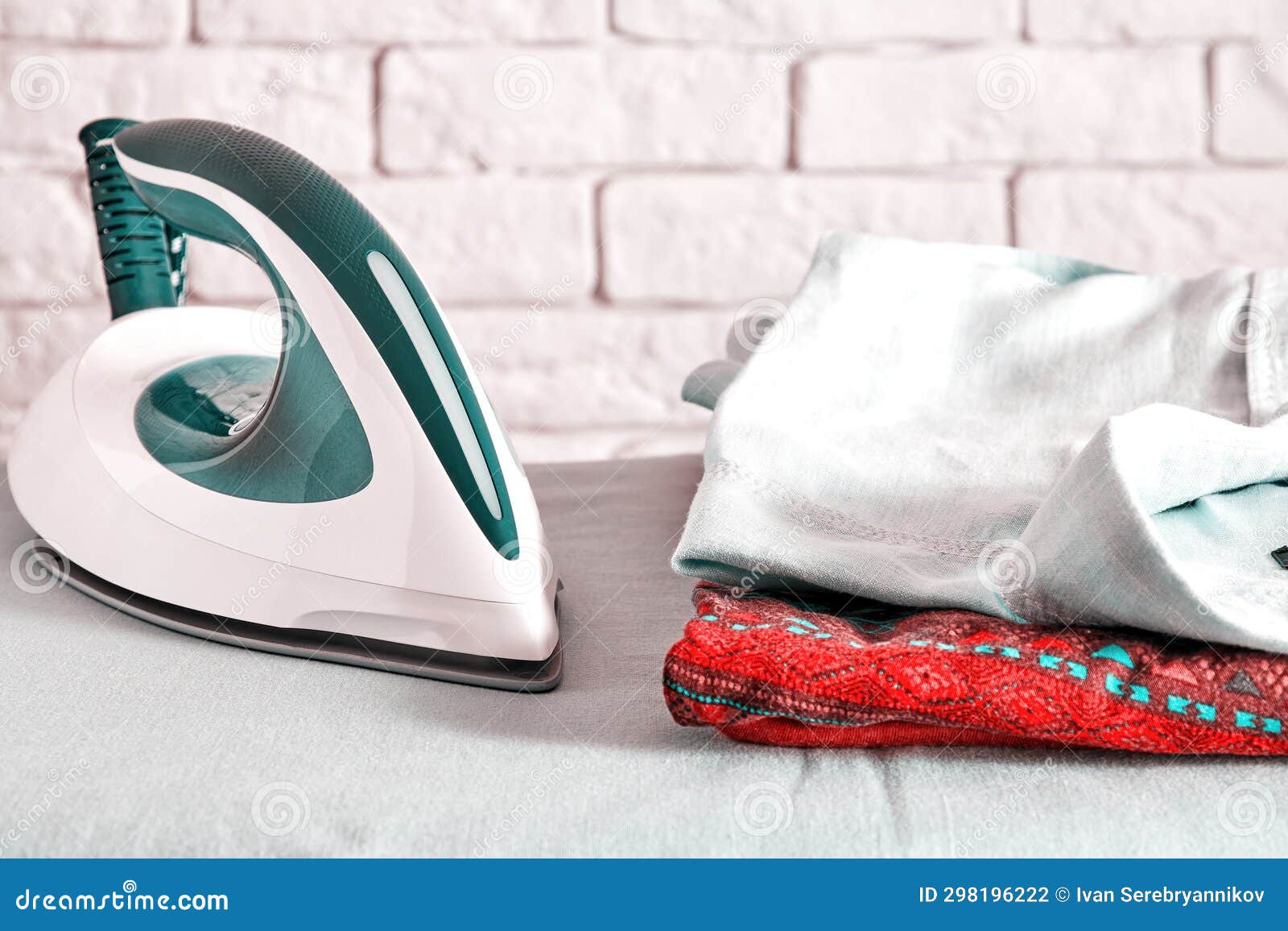 Modern Iron on the Ironing Board with Stack of Ironed Clothes Stock ...