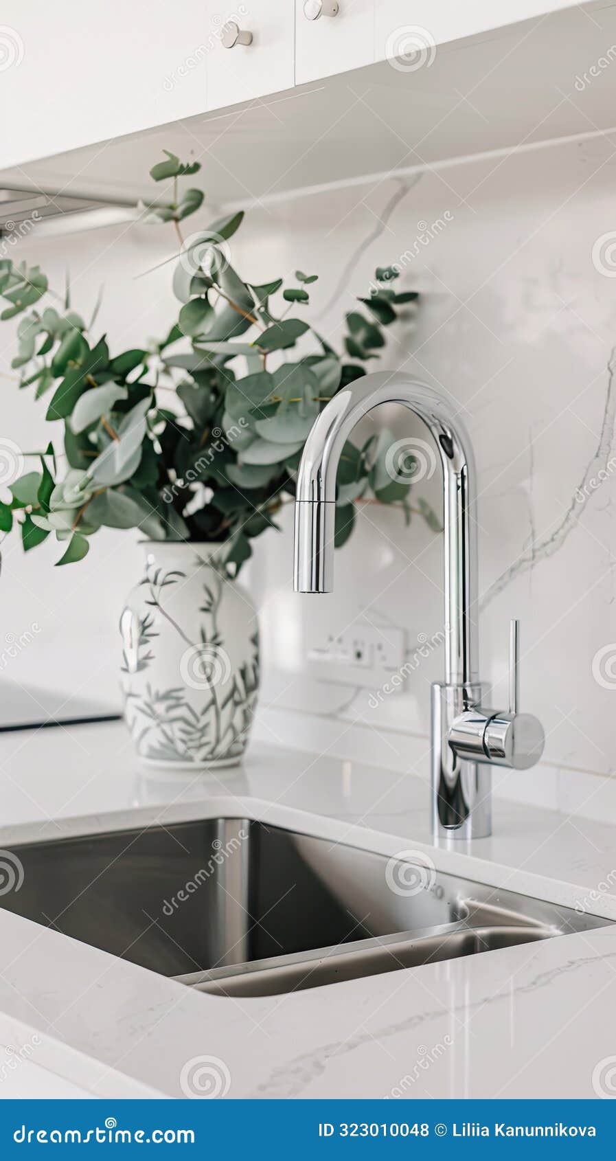 A Modern Kitchen Sink with a Chrome Faucet and a Vase of Greenery on ...