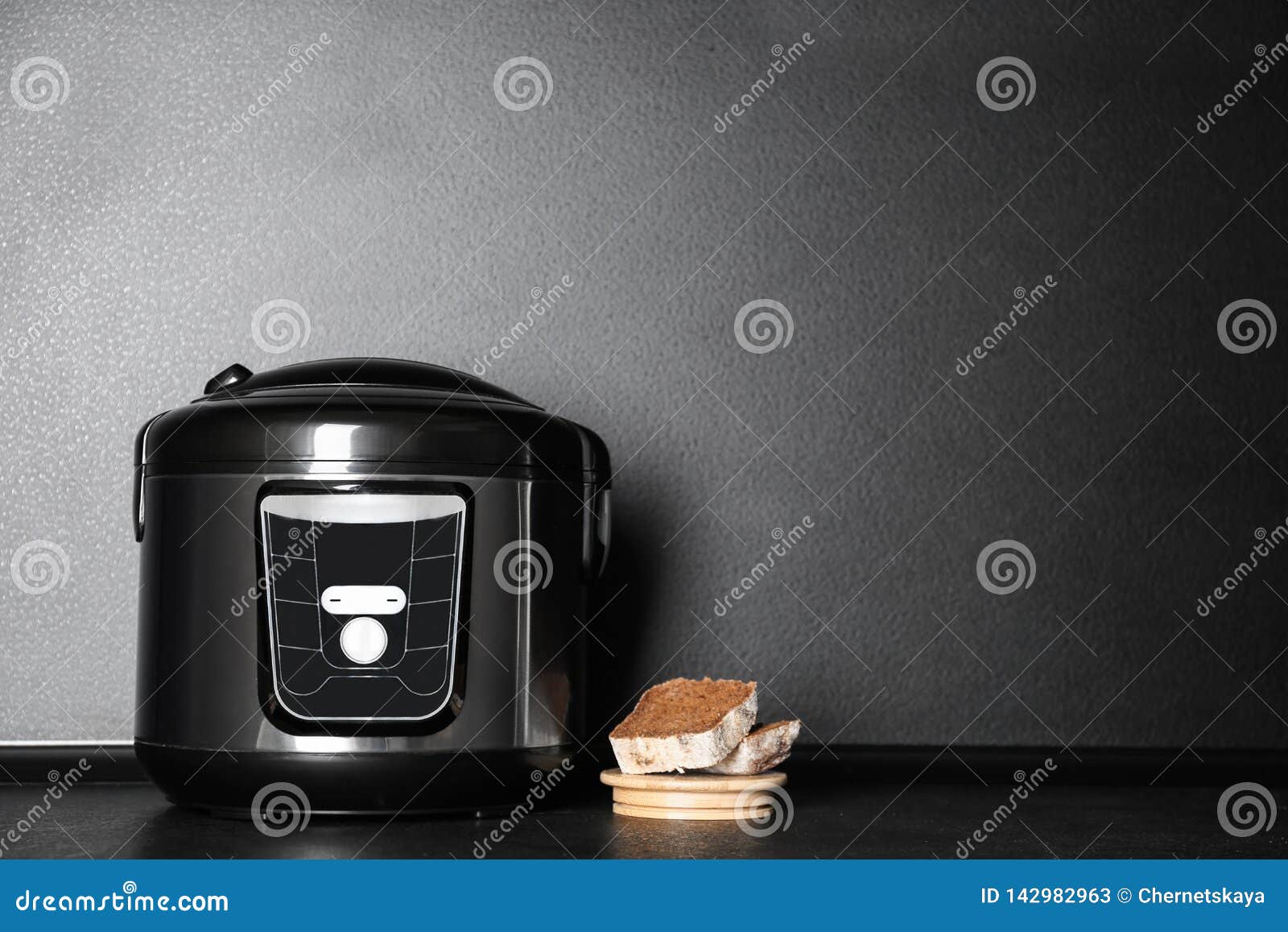 Modern Multi Cooker and Sliced Bread on Table Near Dark Wall Stock ...