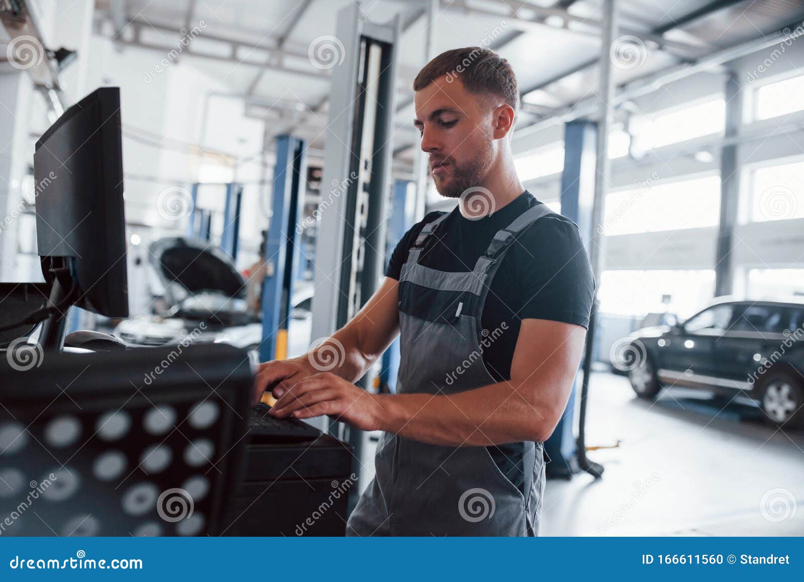 Modern Technologies. Man at the Workshop in Uniform Use Computer for ...