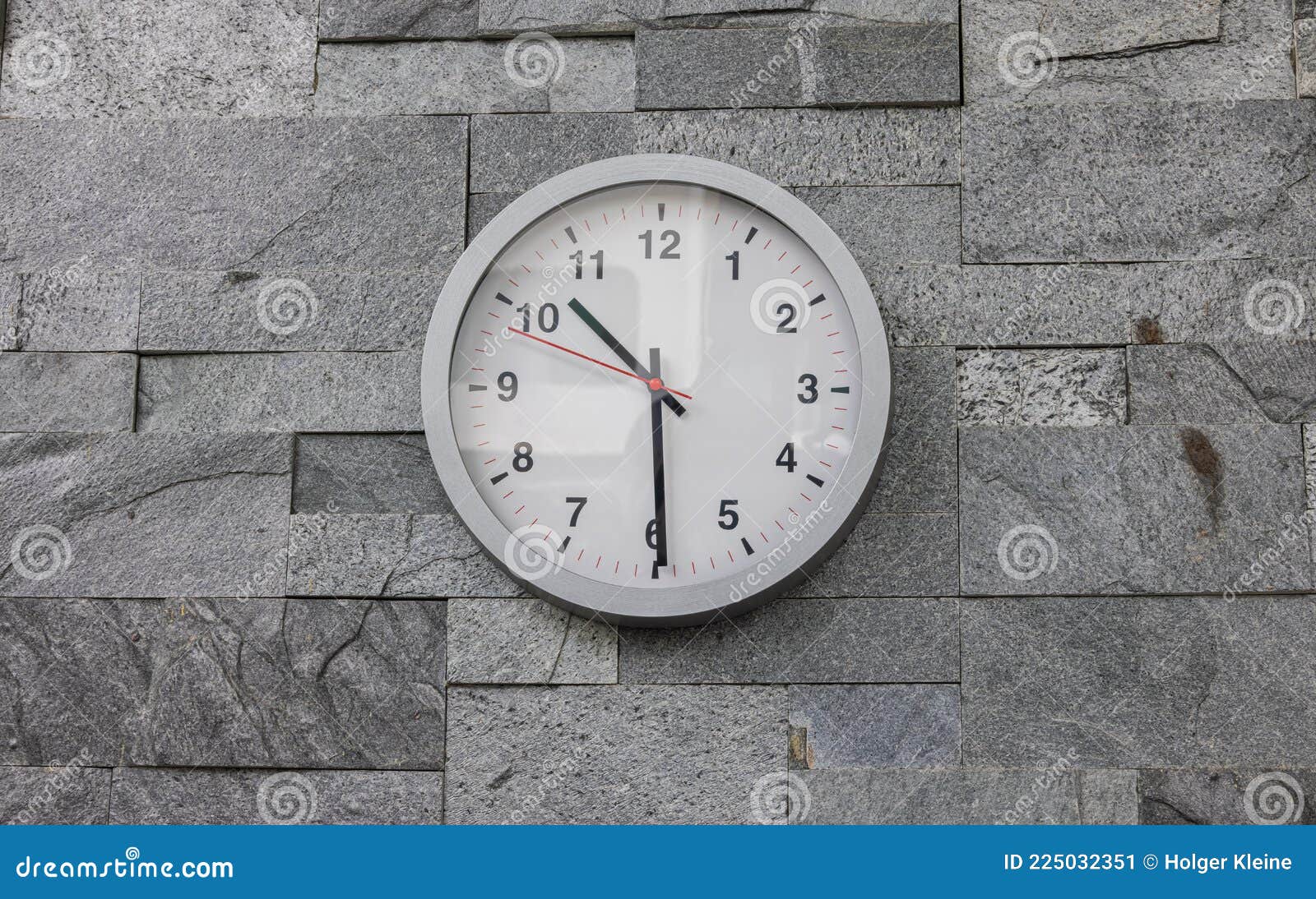 Modern Wall Clock on a Wall Tiled with Rustic Tiles. Stock Image ...