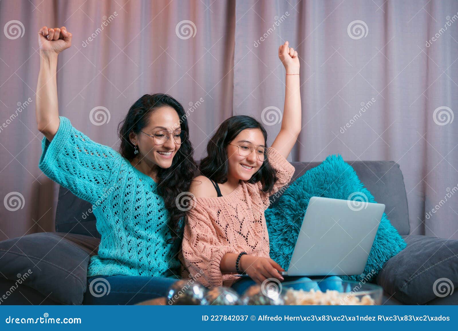 Mom And Daughter Watching A Laptop Sitting On The Sofa At Home The Two