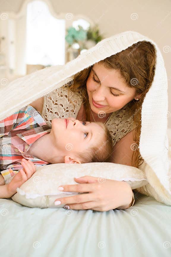Mom Gently Looks At Her Son They Lying On Bed Covered With Bedspread