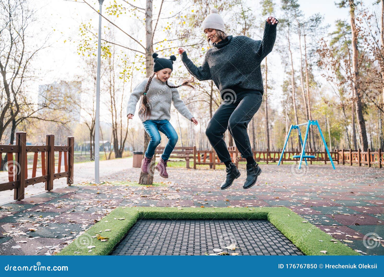 Mom And Her Daughter Jumping Together On Trampoline In Autumn Park
