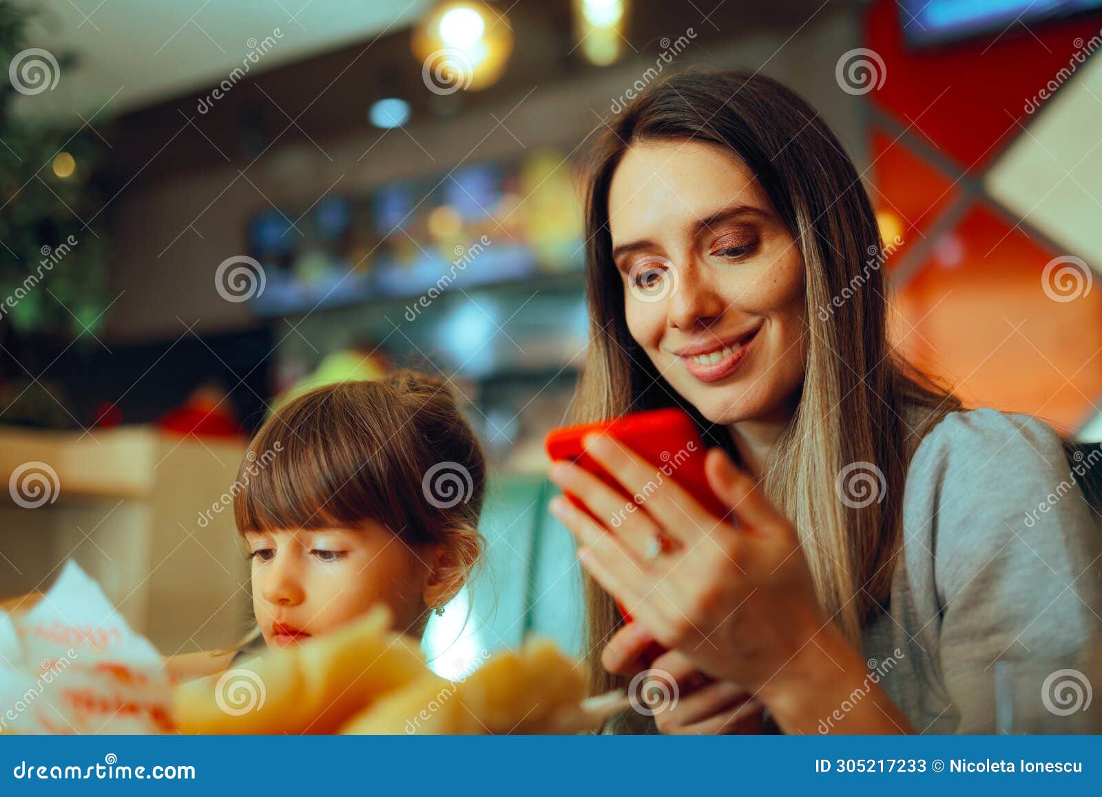Mother Checking Her Phone at the Table in a Restaurant Stock Image ...
