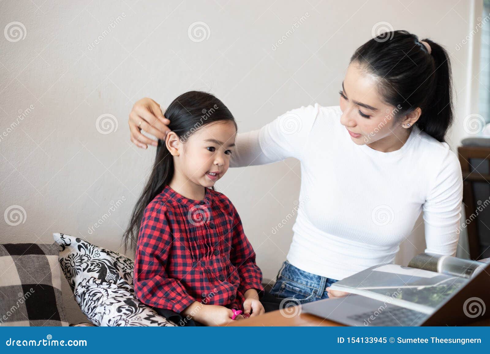 Mom is Teaching Her Daughter To Read a Book and Playing Notebook Stock ...