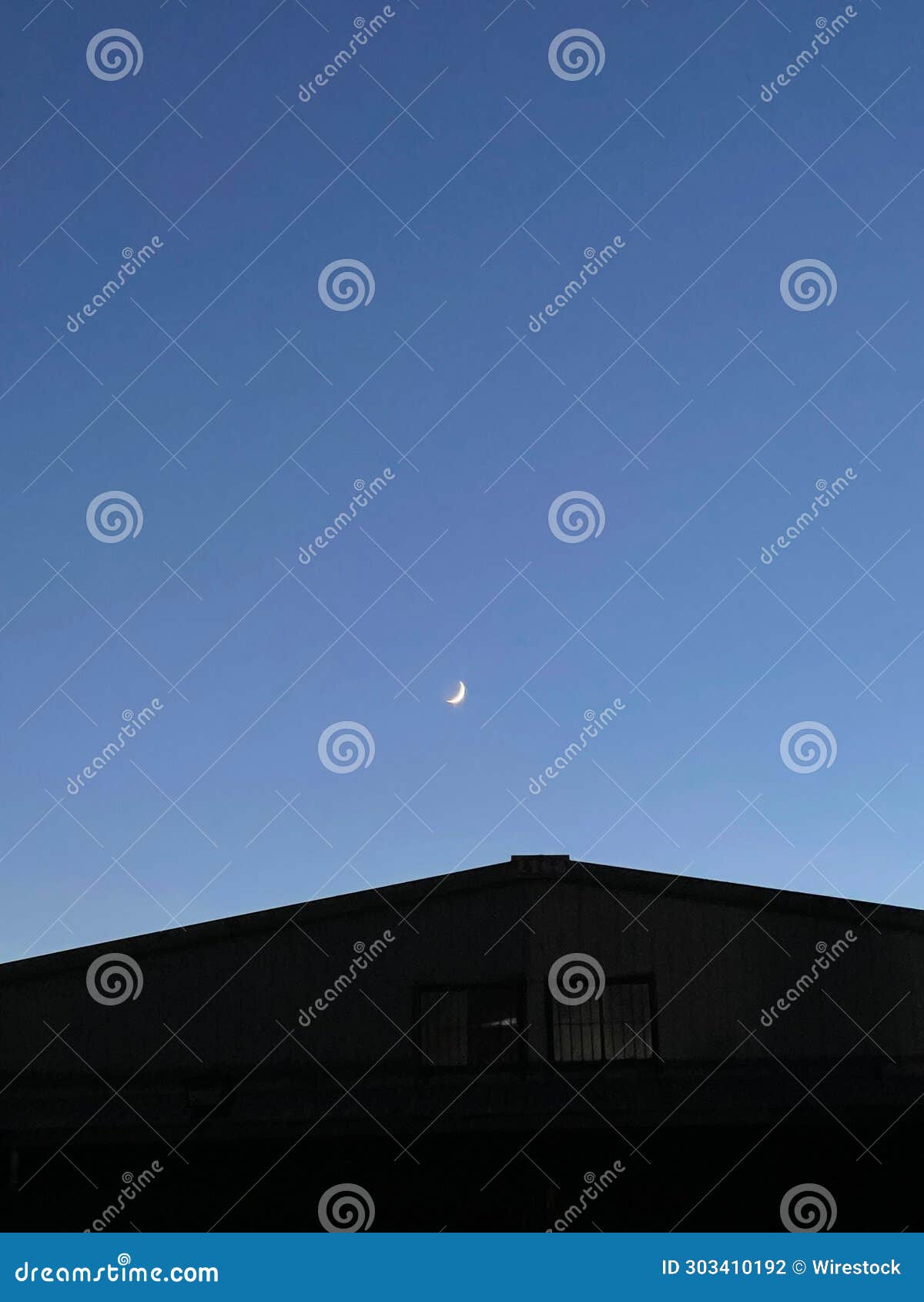 The Moon in a Clear Sky Behind a Building with Some Windows Stock Photo ...