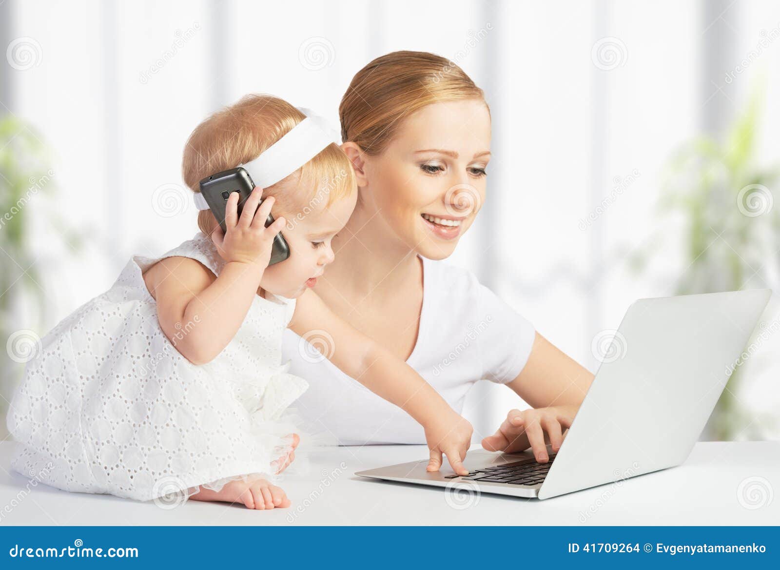 Mother with Baby Daughter Works with a Computer and Phone Stock Photo ...