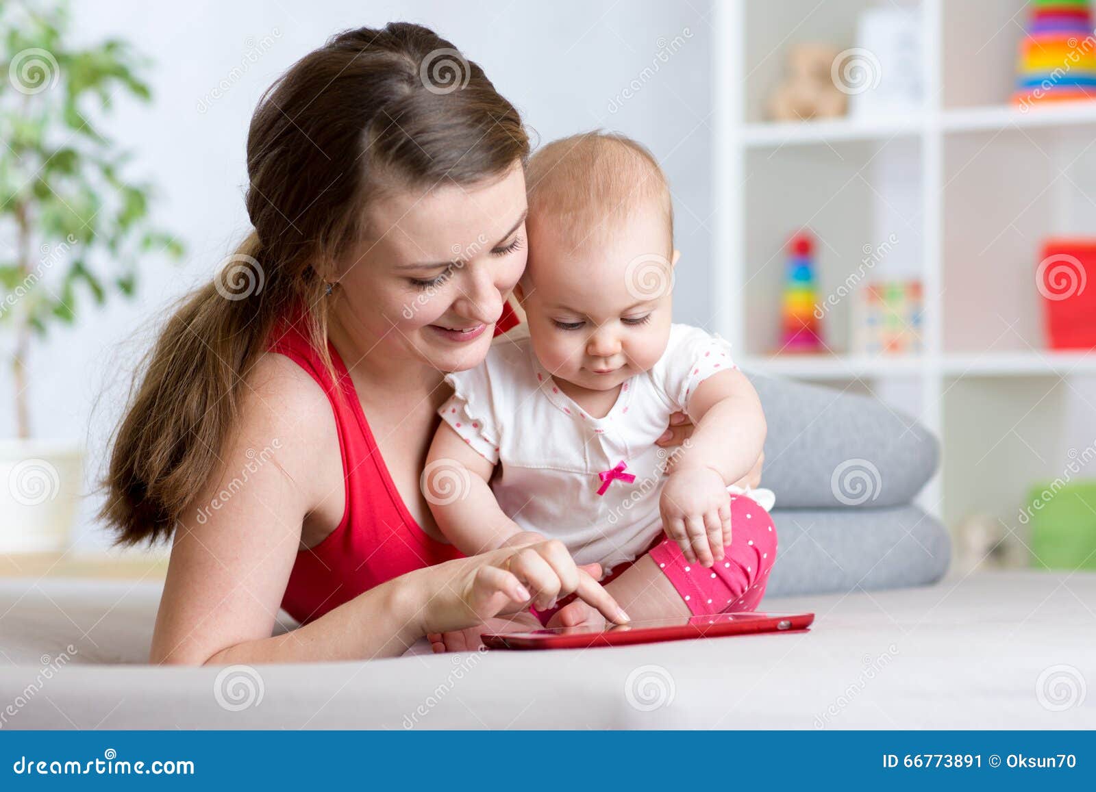 Mother and Baby are Looking To Play Tablet Computer on the Couch at ...