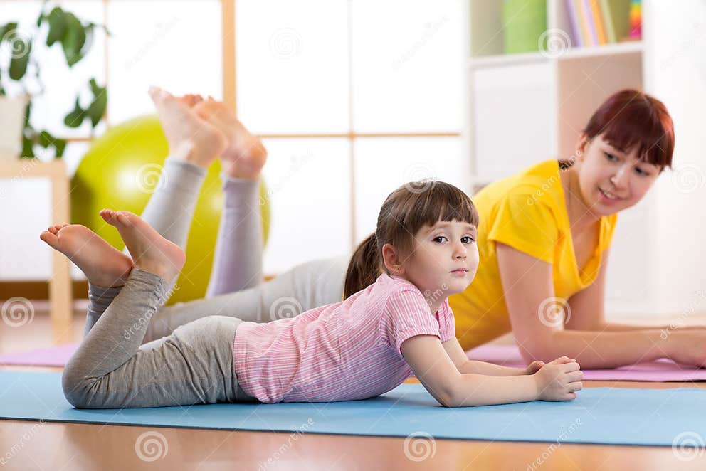 Mother And Daughter Doing Gymnastics Exercises On Mat At Home Stock