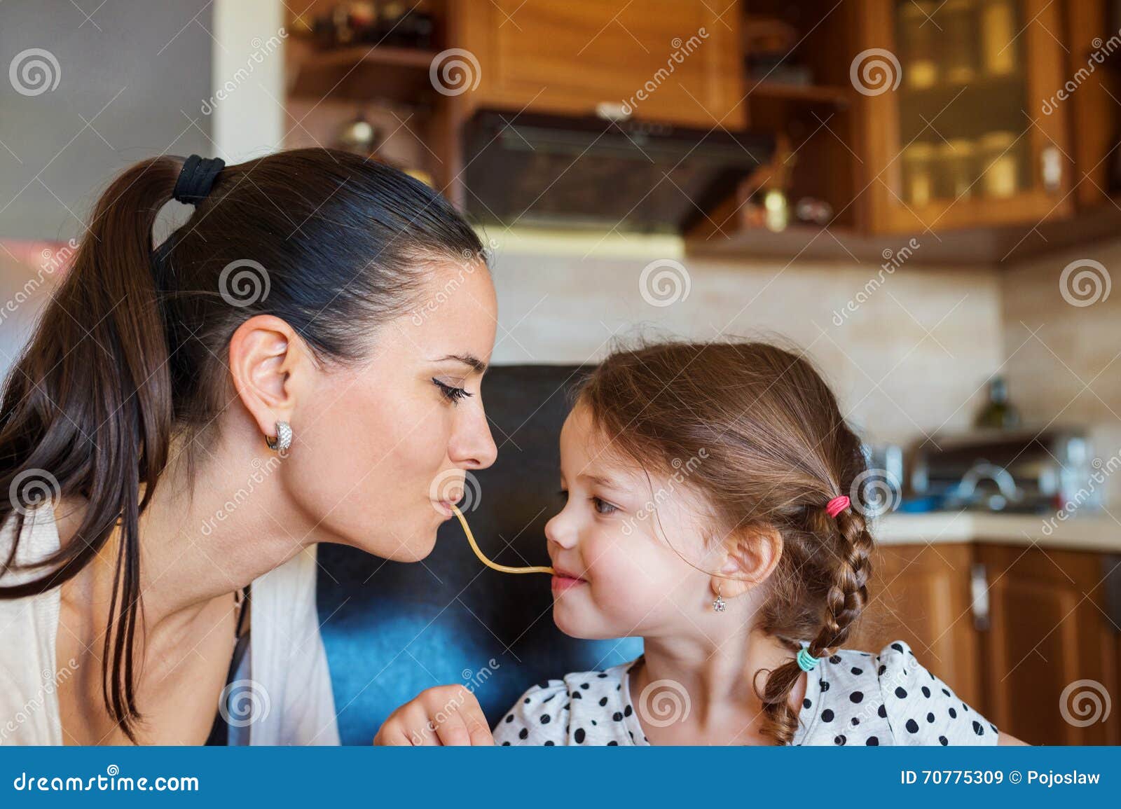 Mother And Daughter In The Kitchen Eating Spaghetti Together Stock