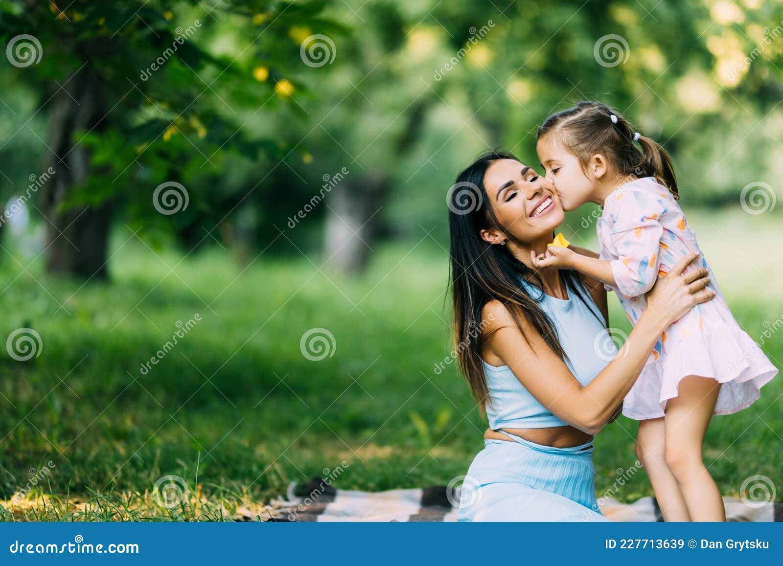 Mother And Daughter Lying On The Lawn Daughter Kiss Her Mother On The