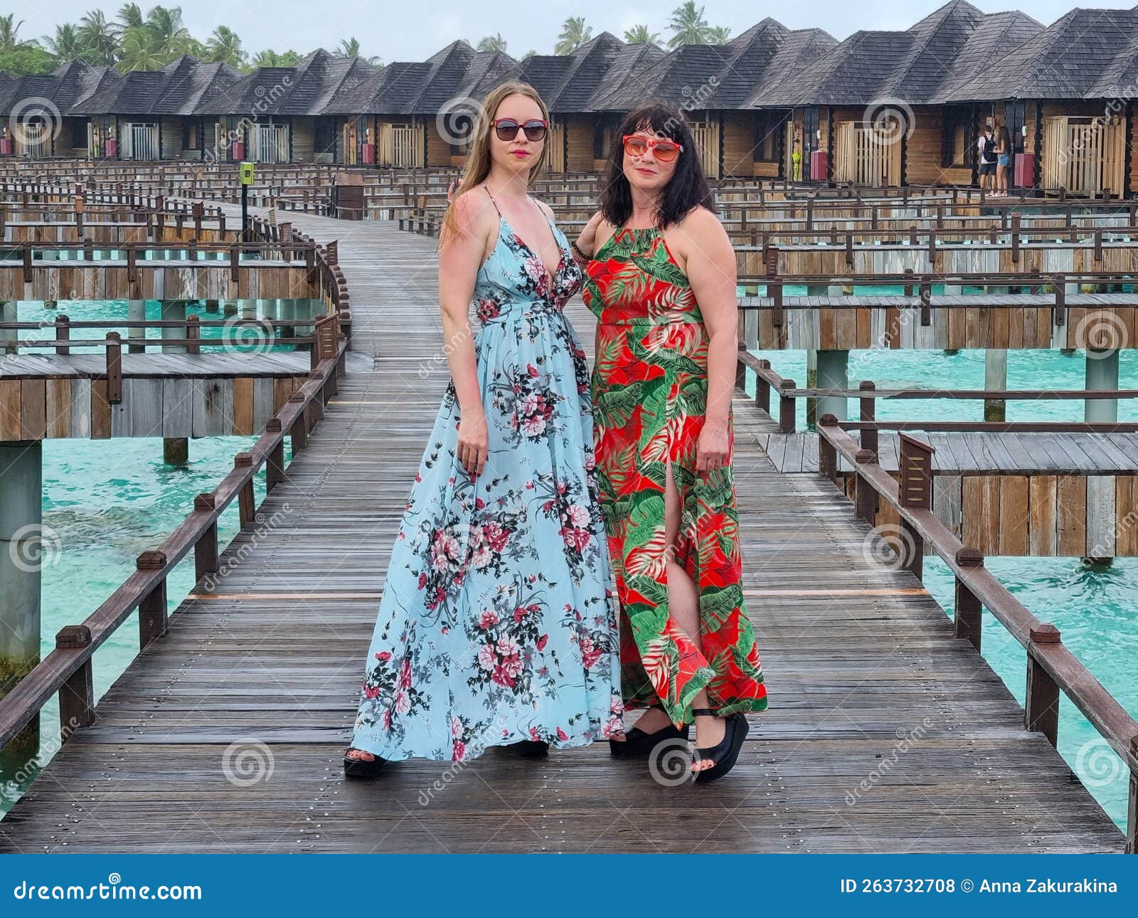 Mother And Daughter In Matching Tropical Dresses Standing Together On