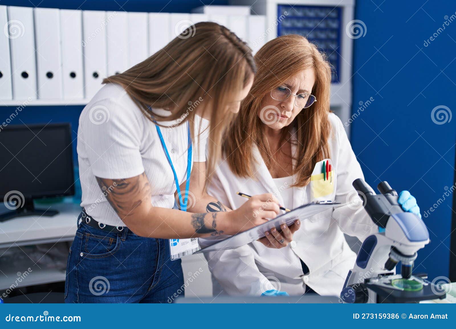 Mother and Daughter Scientists Writing on Document Using Microscope at ...