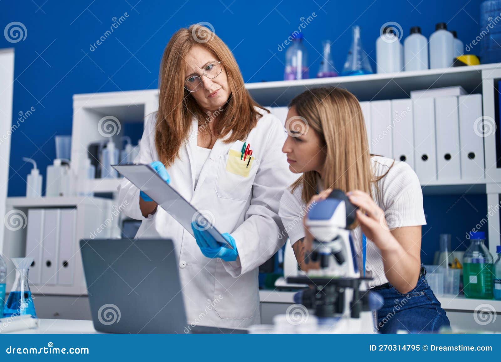 Mother and Daughter Scientists Writing on Document Using Microscope at ...