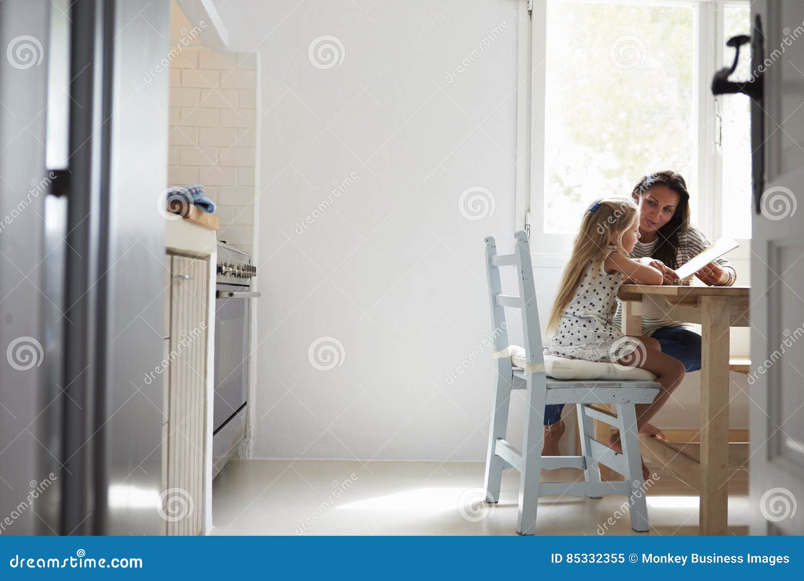 Mother and Daughter Sitting at Kitchen Table Reading Book Stock Image ...