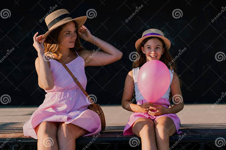 Mother And Daughter Are Sitting In Pink Dresses With Flowing Long Hair