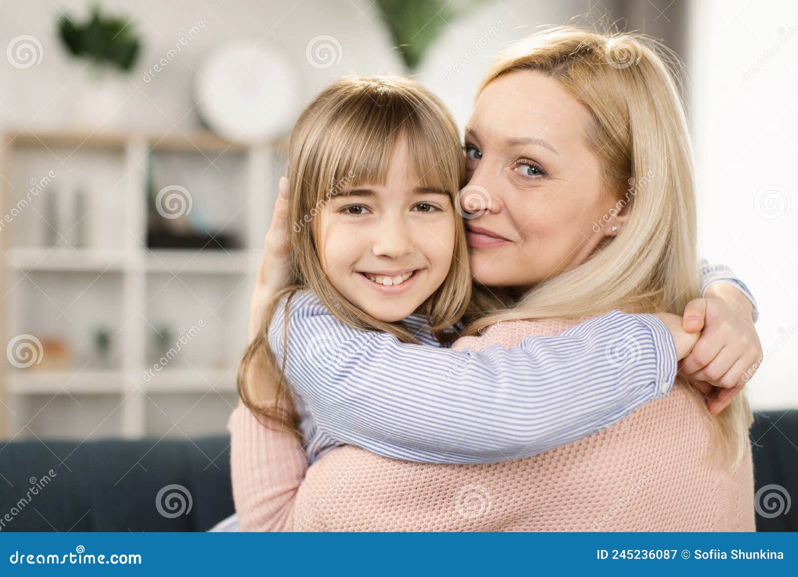 Mother And Daughter Sitting Together On Sofa At Home Embracing Feels