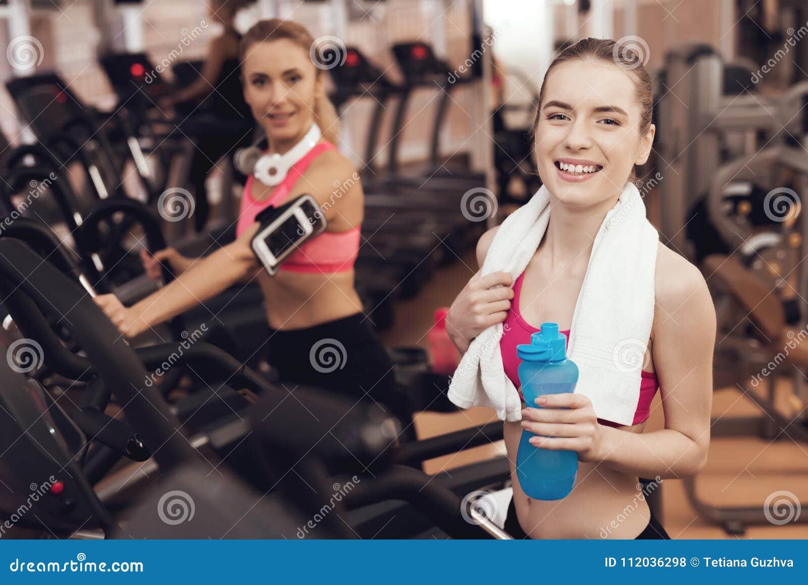 Mother And Daughter Drinking Water On Treadmill In Gym They Look Happy