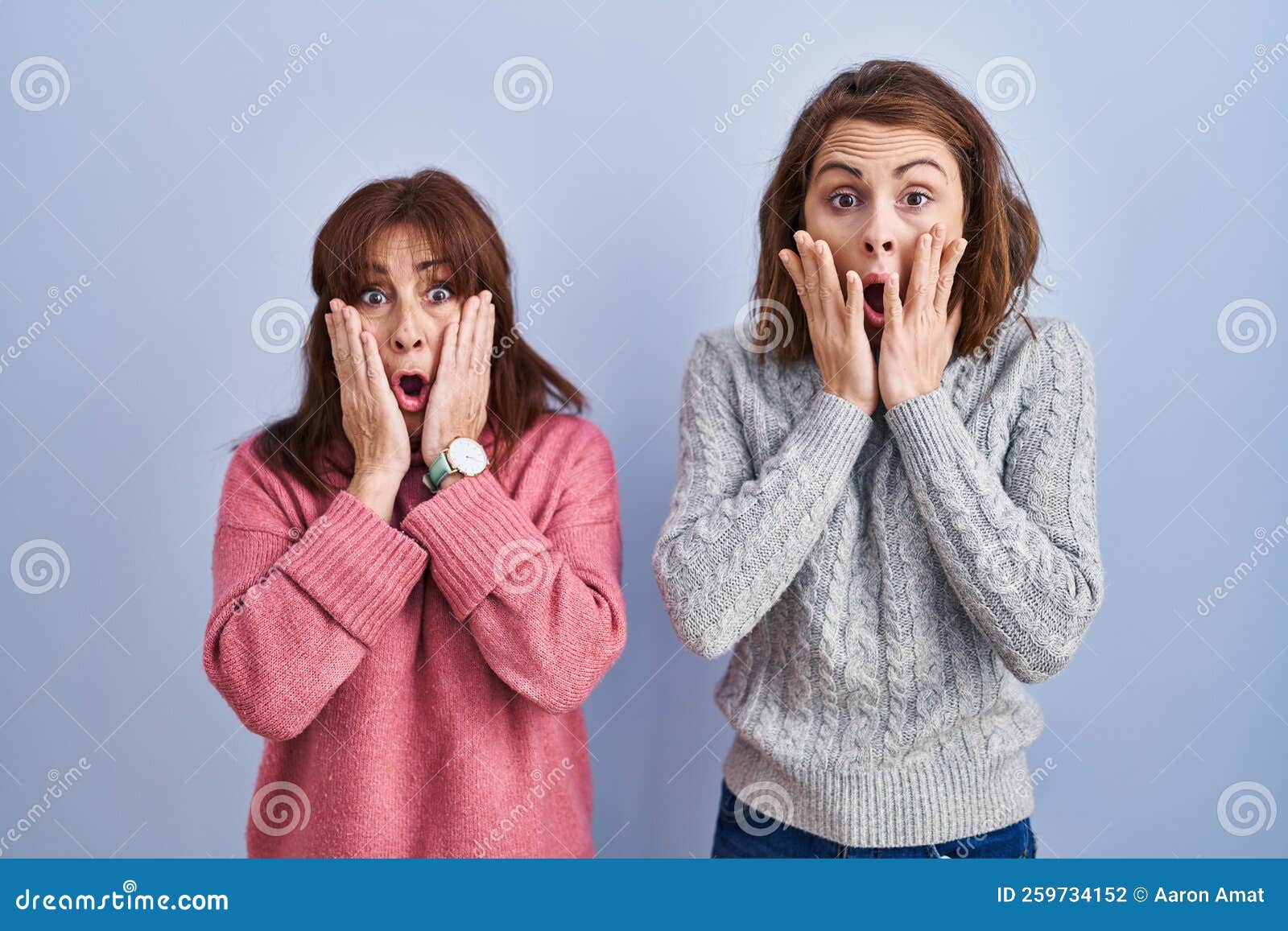 Mother And Daughter Standing Over Blue Background Afraid And Shocked