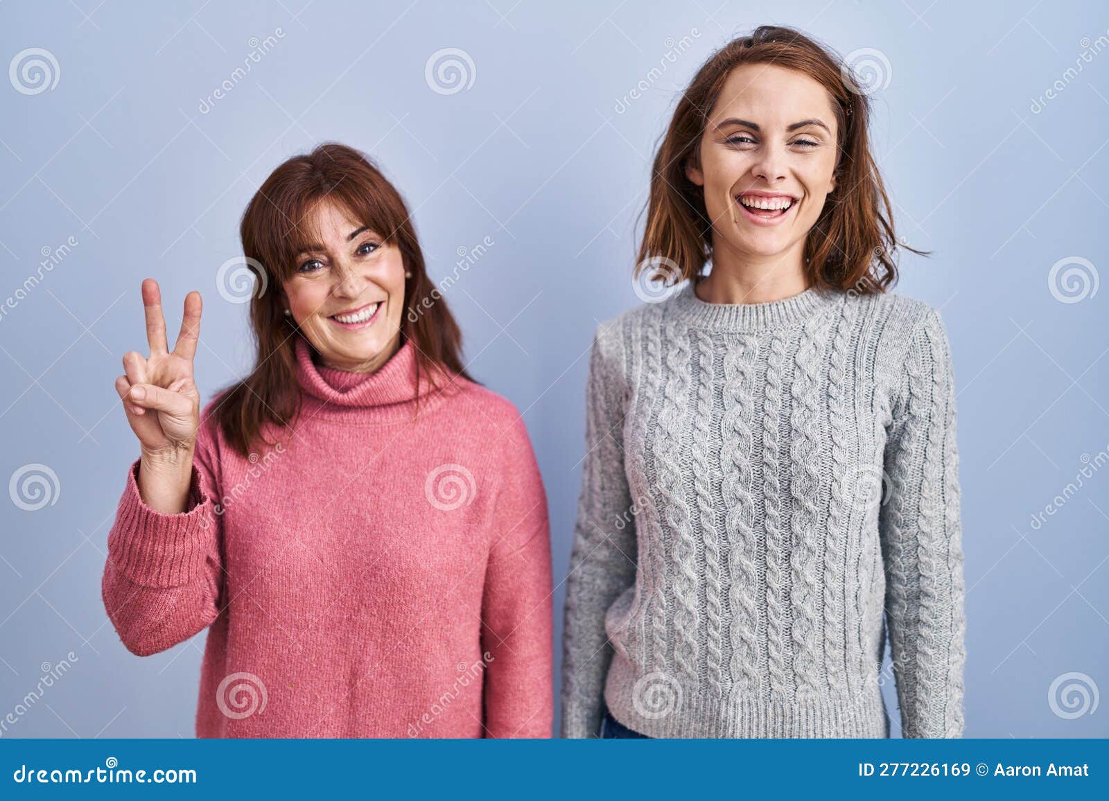Mother And Daughter Standing Over Blue Background Showing And Pointing