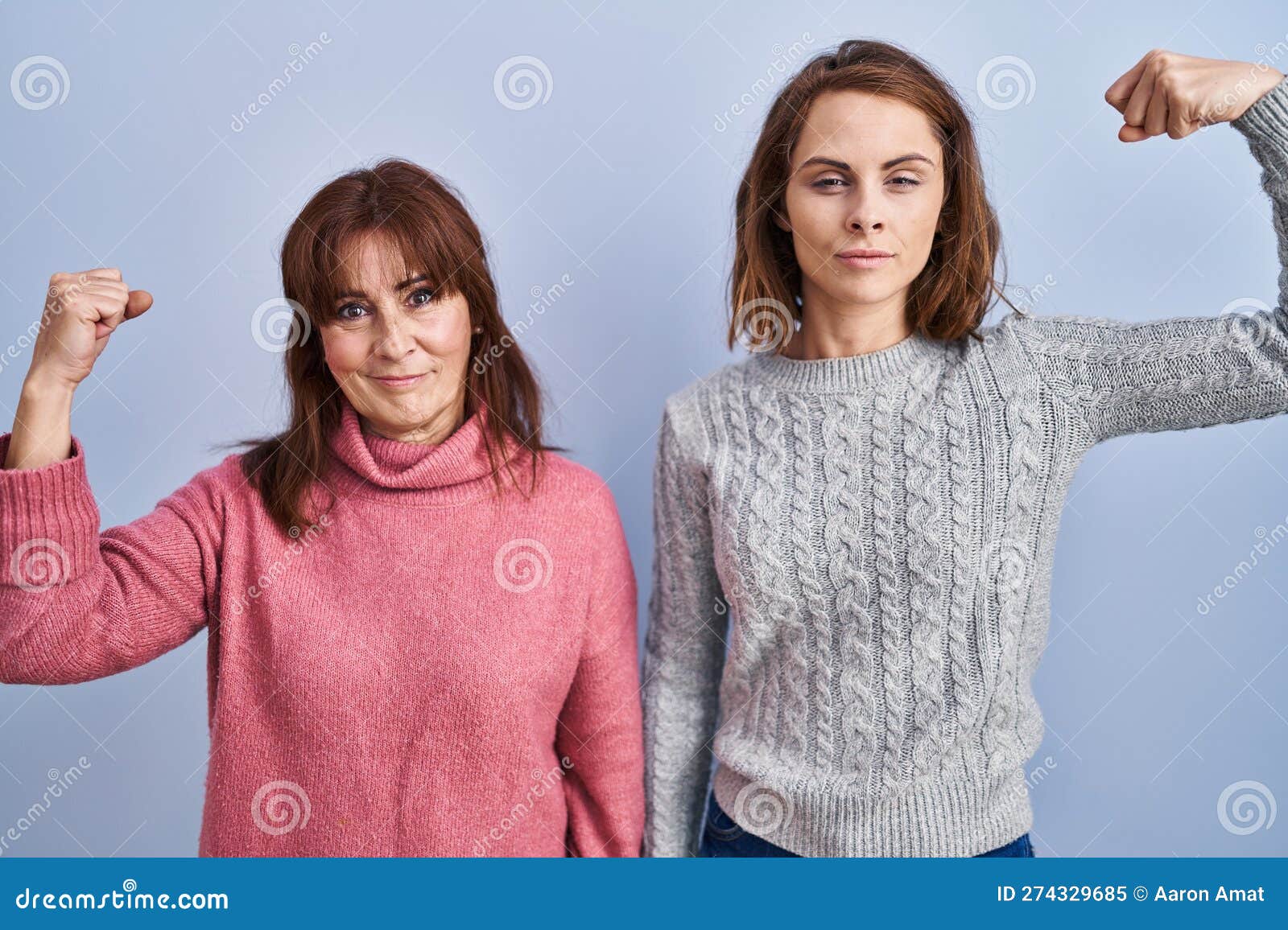 Mother And Daughter Standing Over Blue Background Strong Person Showing