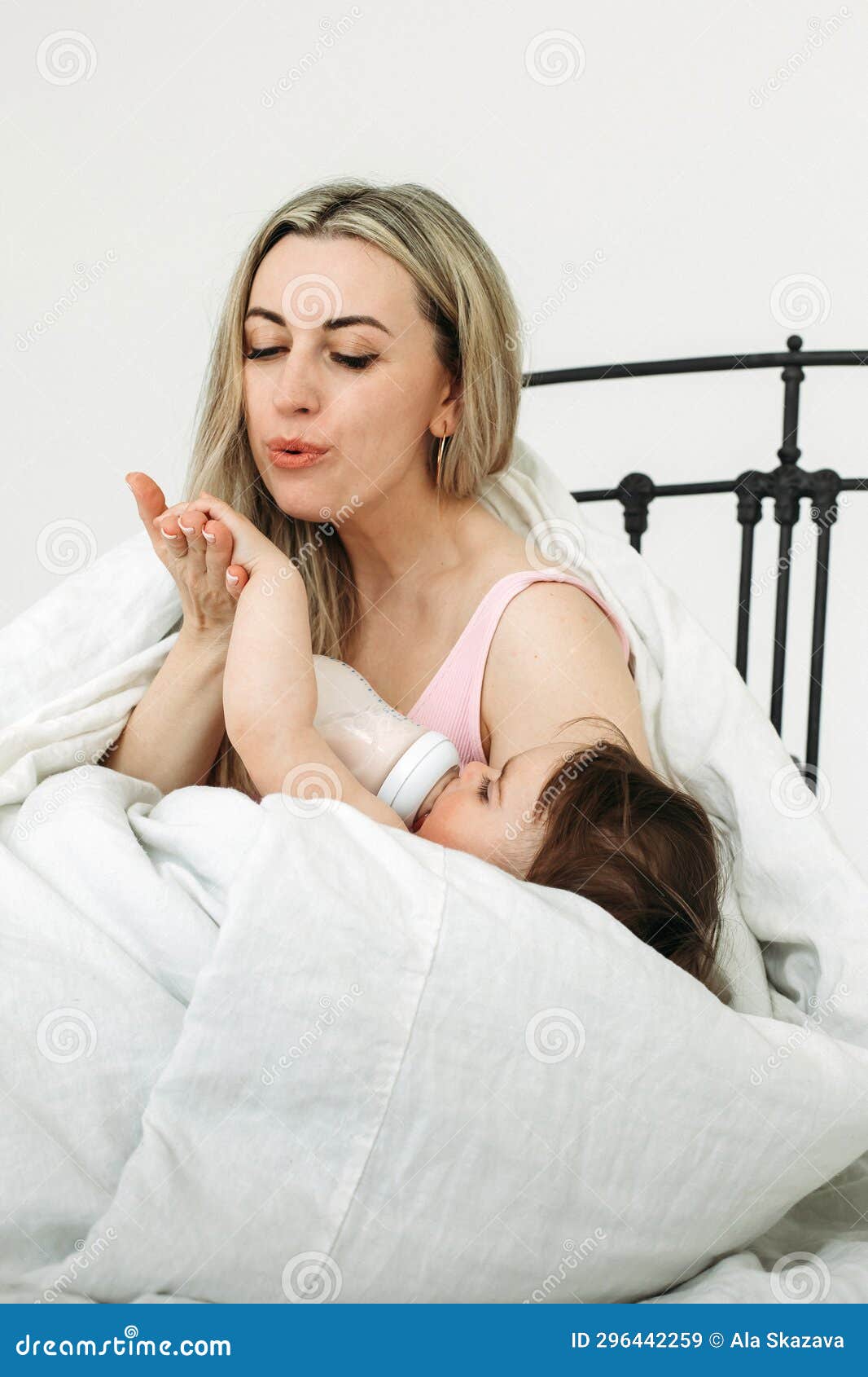 A Mother Feeds Her One Year Old Daughter Formula From A Bottle Wraps