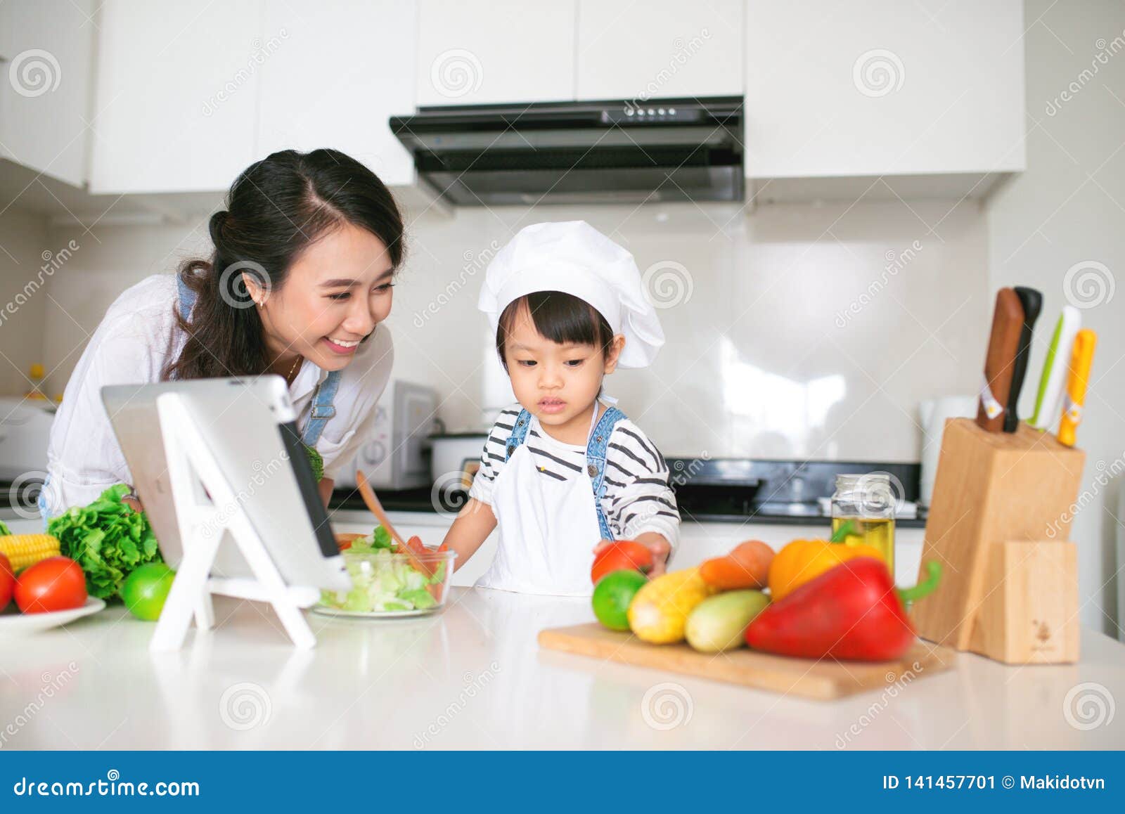 Mother with Her Daughter Preparing Lunch in the Kitchen and Enjoying ...