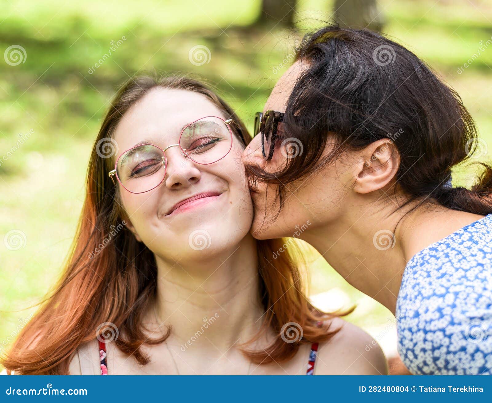 Mother Kissing Her Teenage Daughter With Dyed Hair And Glasses Against