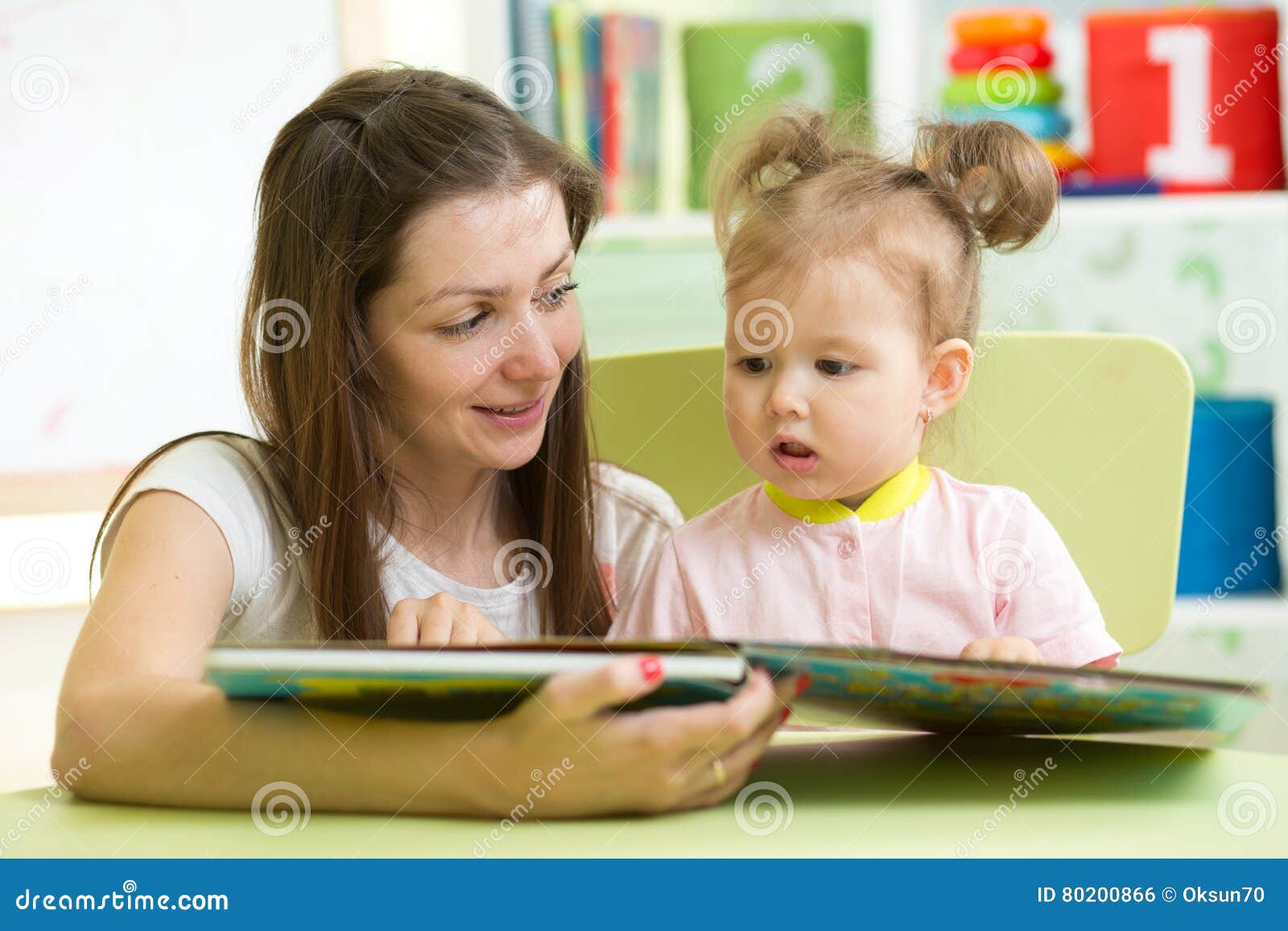 Mother Reading with Her Daughter at Table Stock Photo - Image of ...